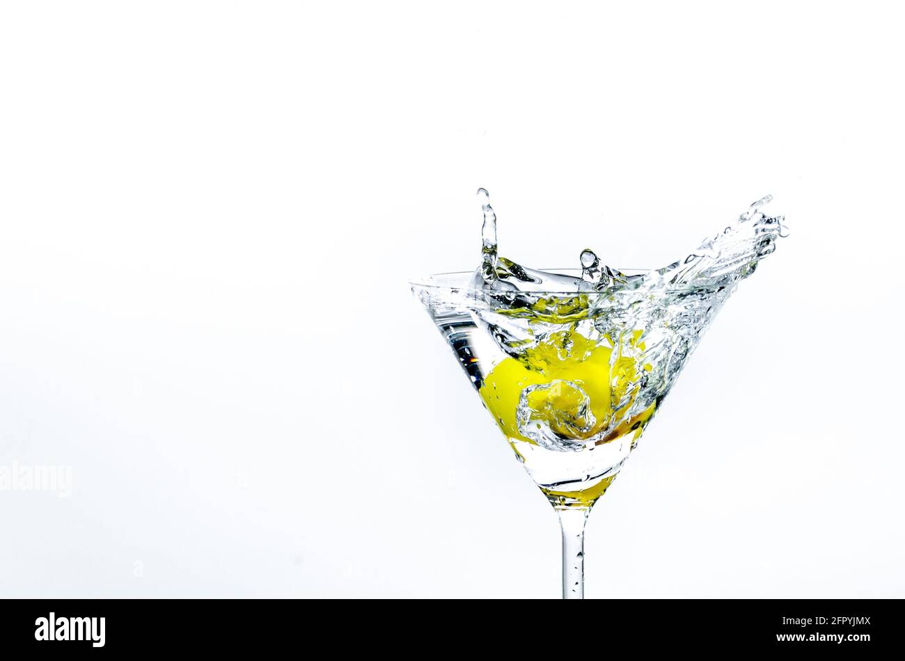 Cocktail in a triangular glass with a lemon cap in it making splashes ...