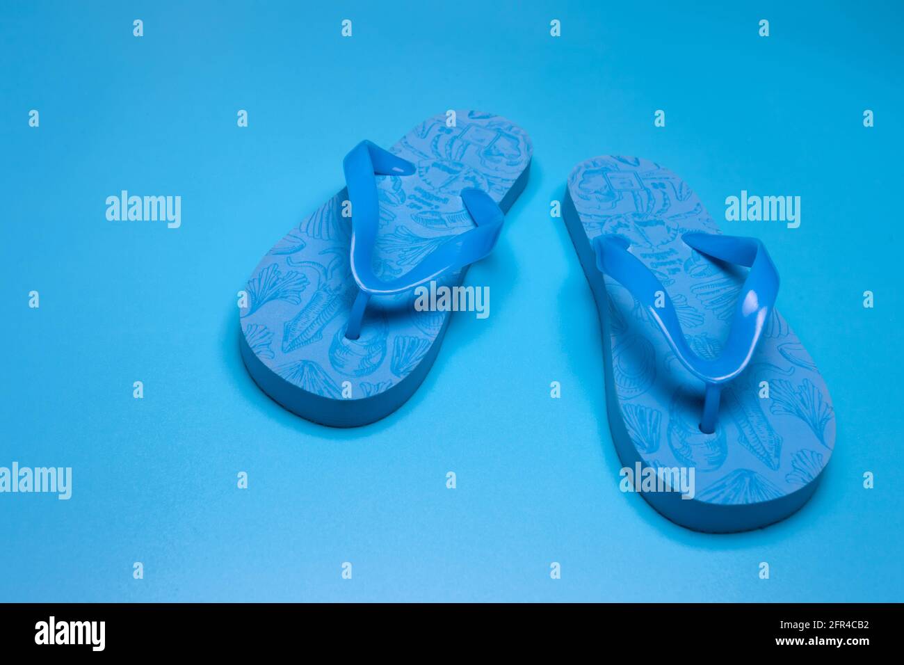 Blue rubber flip-flops isolated over blue background, pair of thongs ...