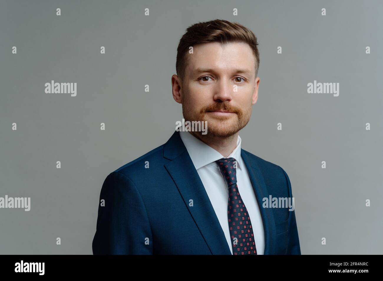 Handsome unshaven man in suit posing against grey background Stock ...