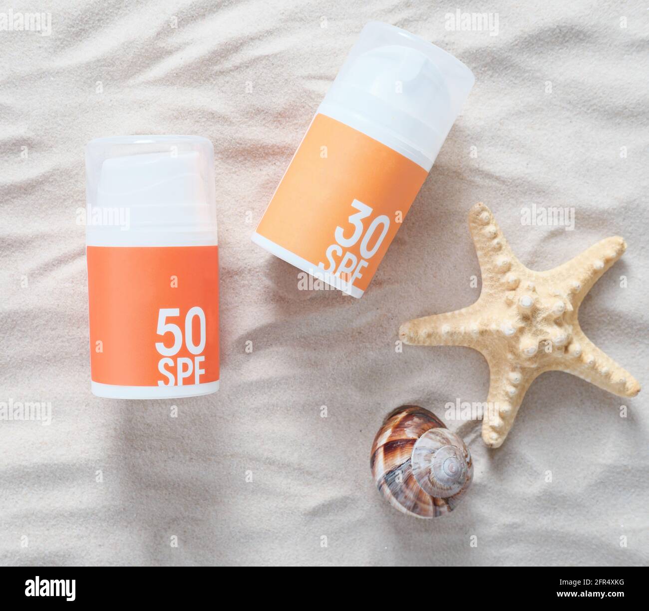 sun tan protection creme bottles on a sand next to starfish and ...
