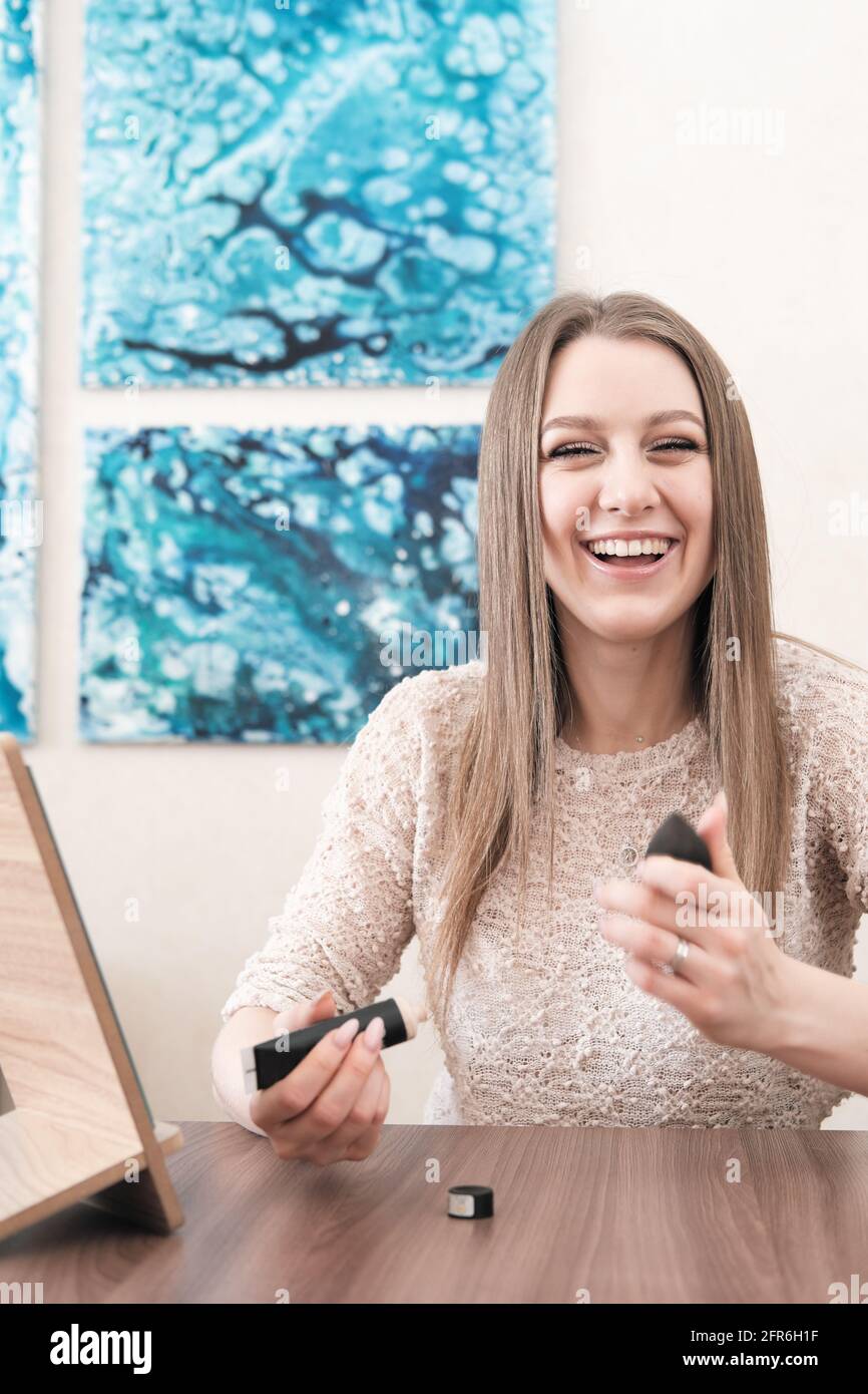 happy laughing woman holding foundation tube and a sponge for make up ...