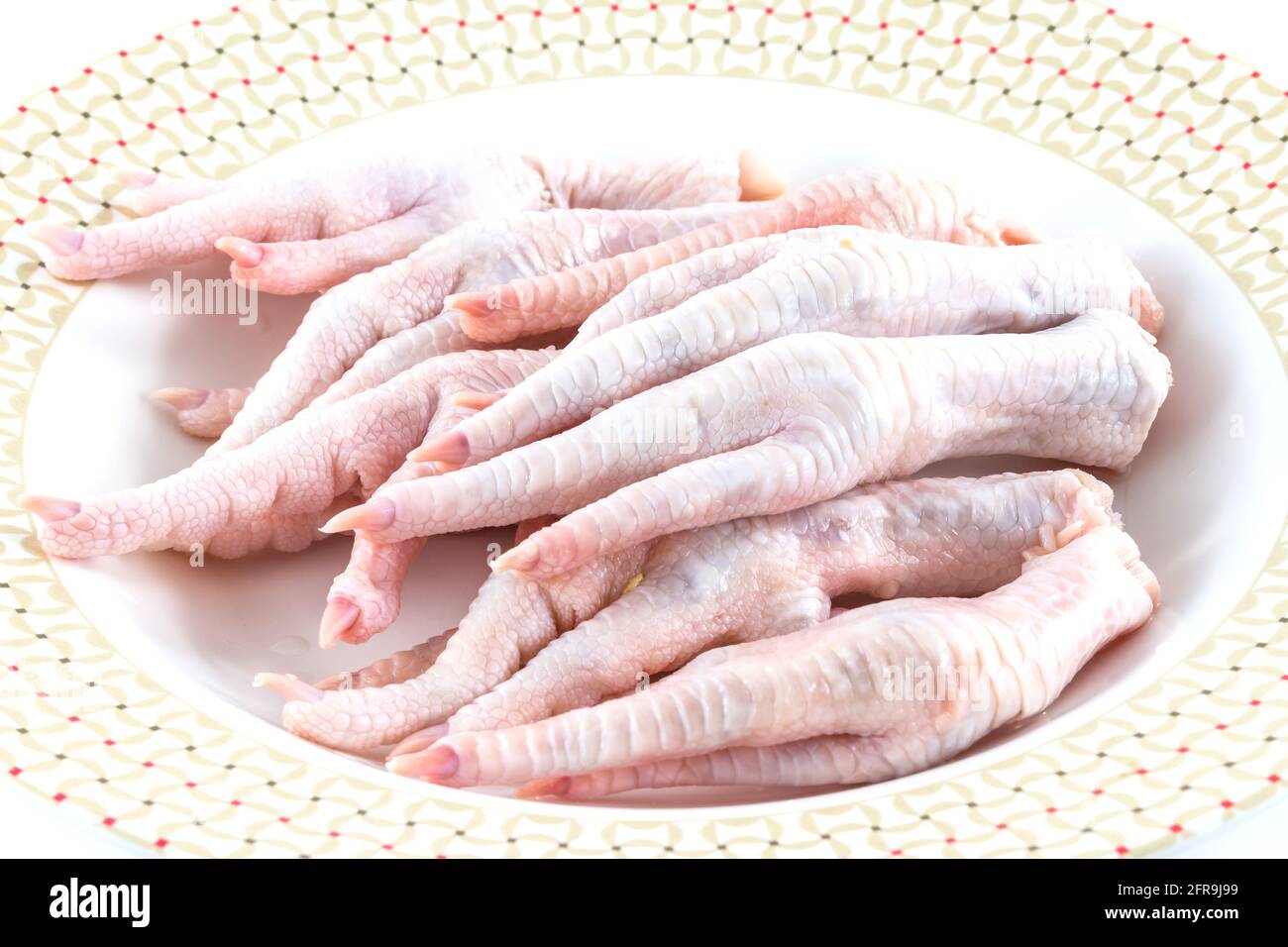 Chicken feet on white disk on white background Stock Photo - Alamy