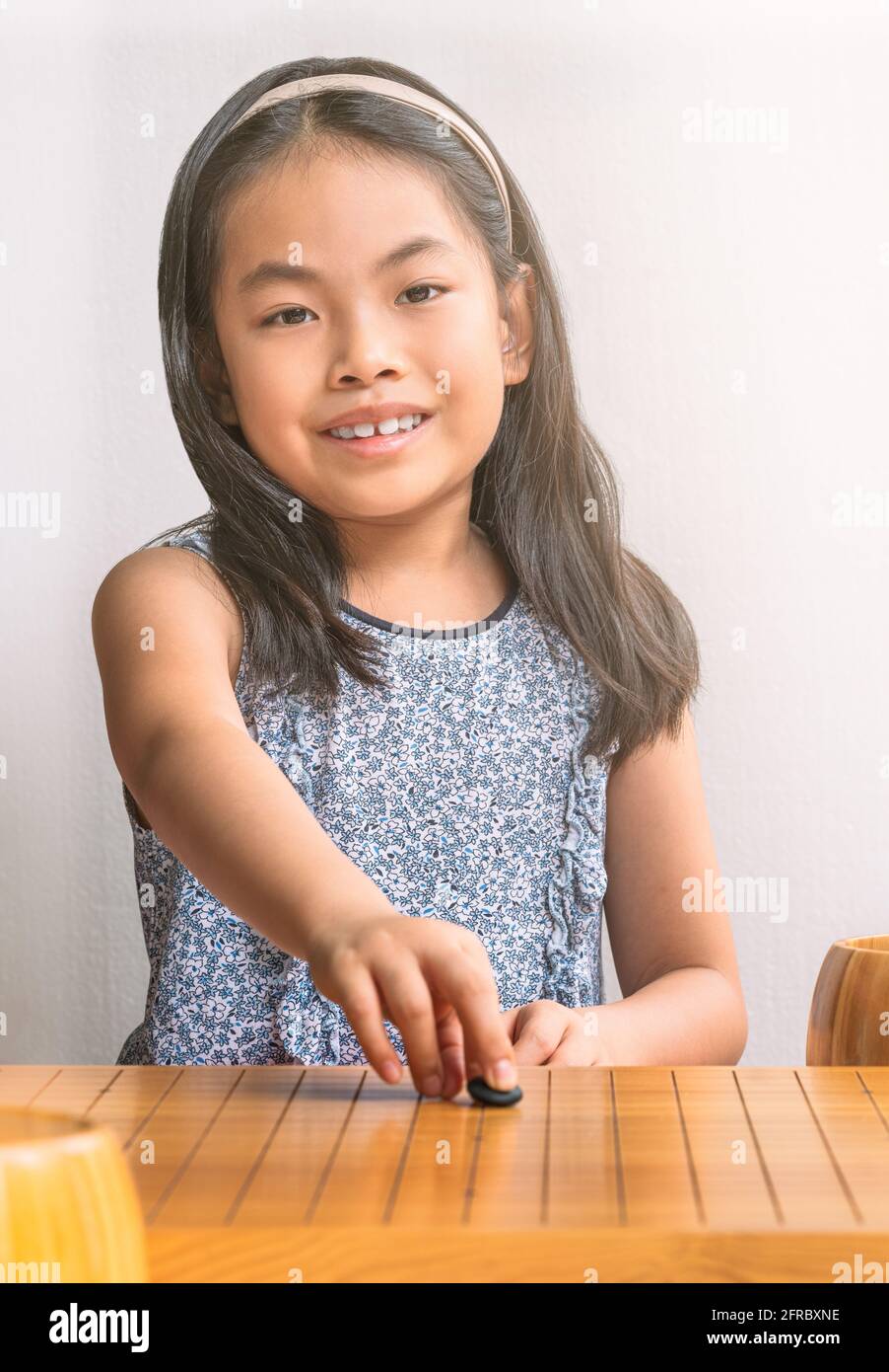 Portrait Asian child girl is playing Go with the first move of black ...