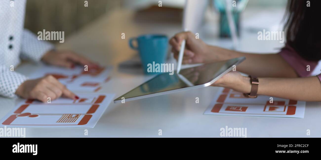 Side view of UI developer team consulting on their project with tablet ...