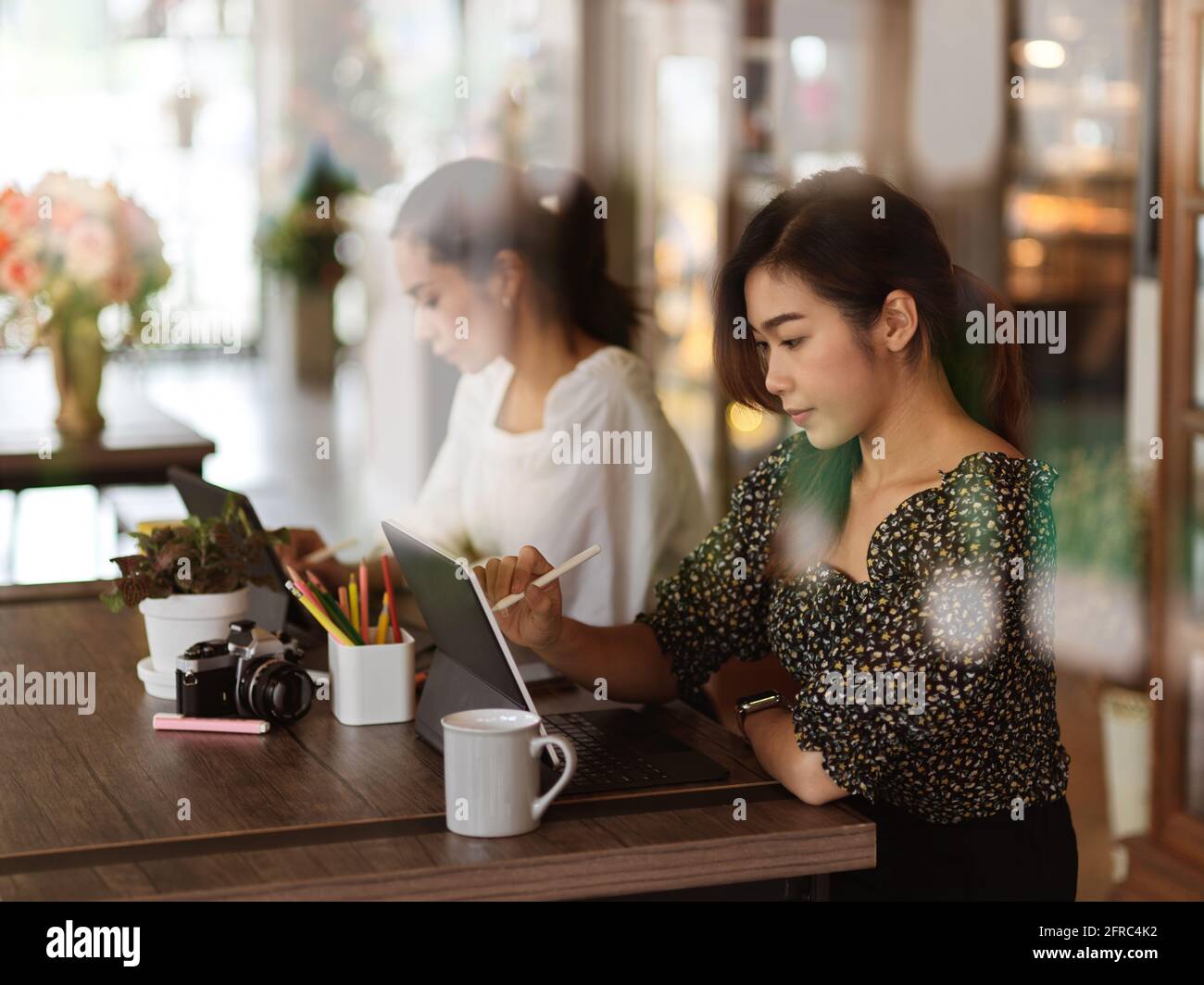 View through glass wall of two female working with office supplies in ...