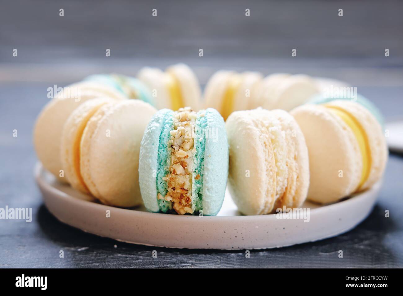 close up view of pastel colored macaroons on a plate. lemon nut filling ...