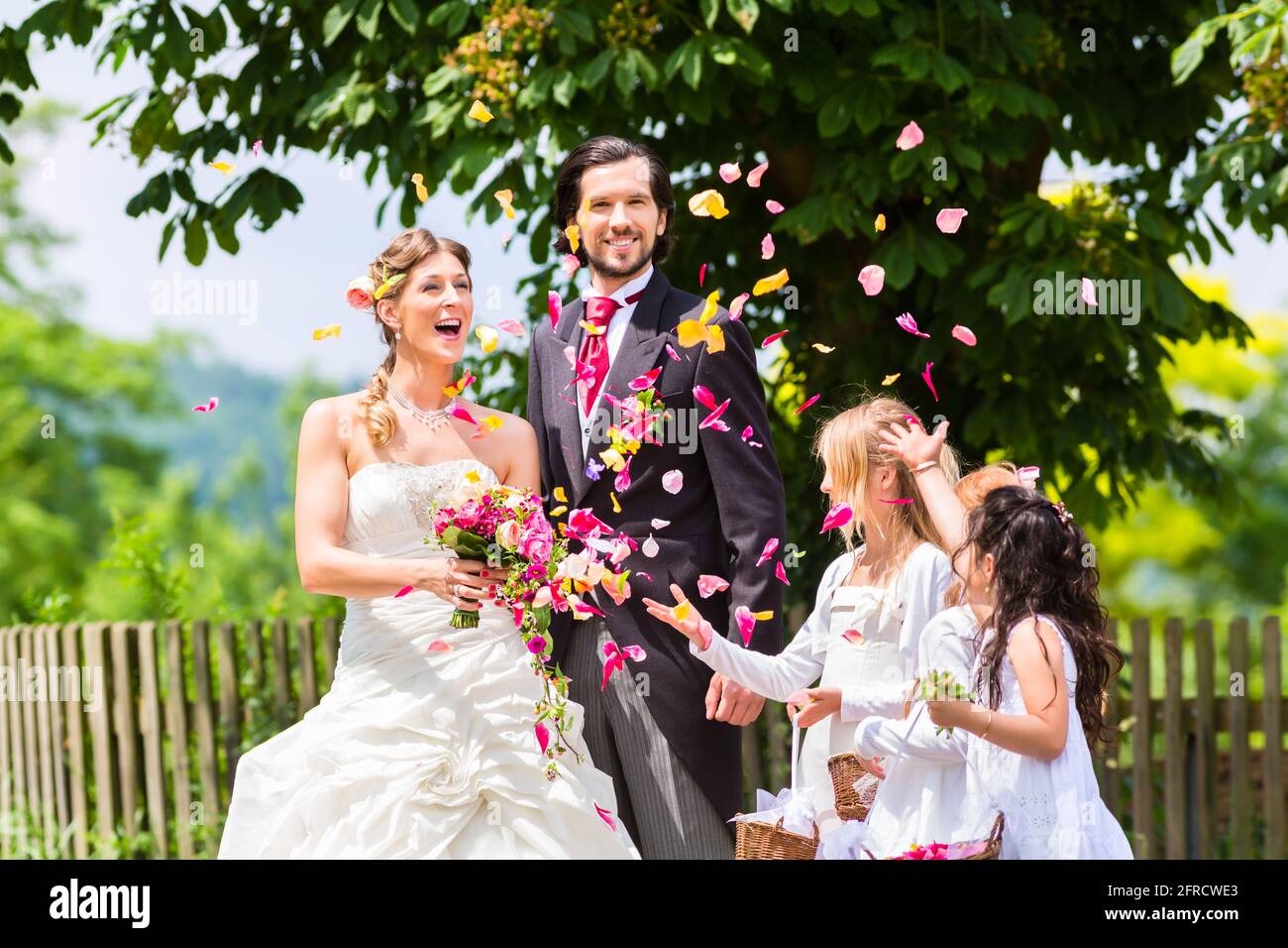 Wedding couple bride and groom with flower children or bridesmaid in ...