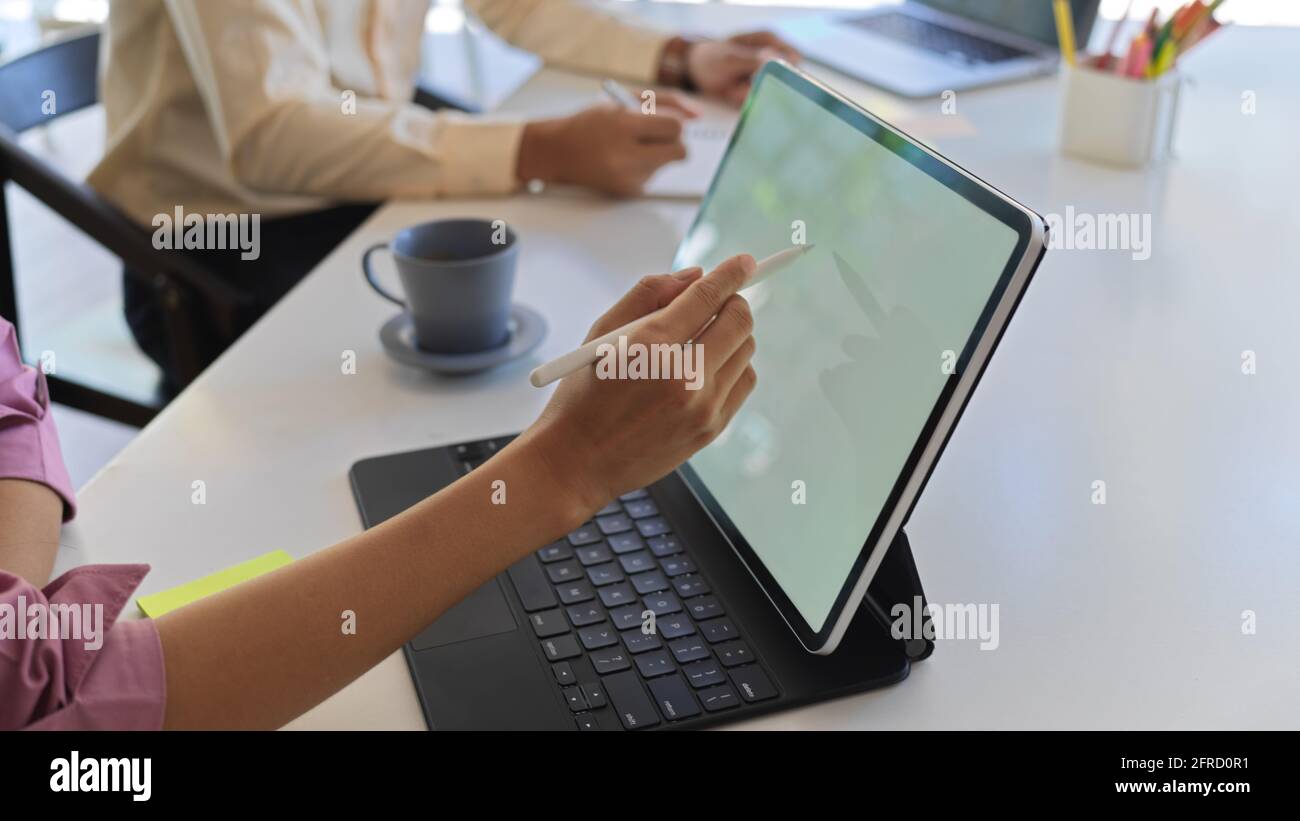 Side view of female hands with stylus pen working on mock up digital ...