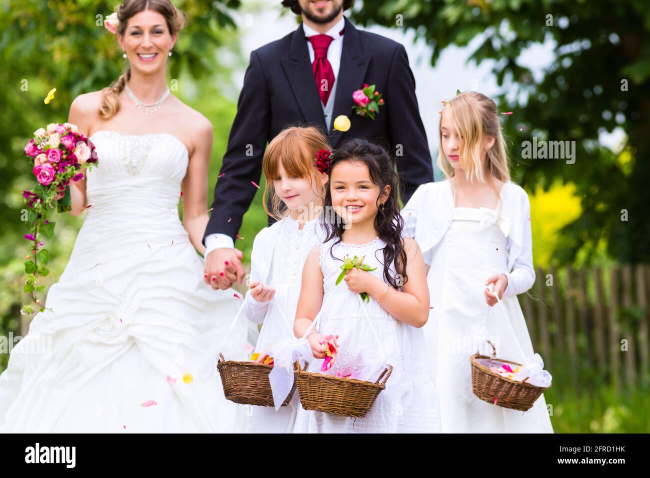 Wedding couple bride and groom with flower children or bridesmaid in ...