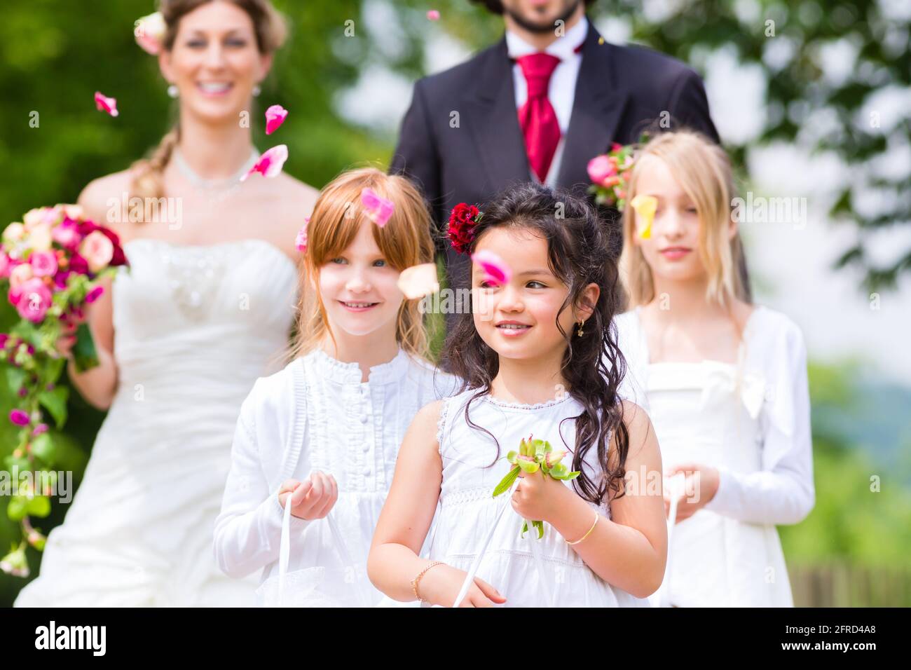 Wedding couple bride and groom with flower children or bridesmaid in ...