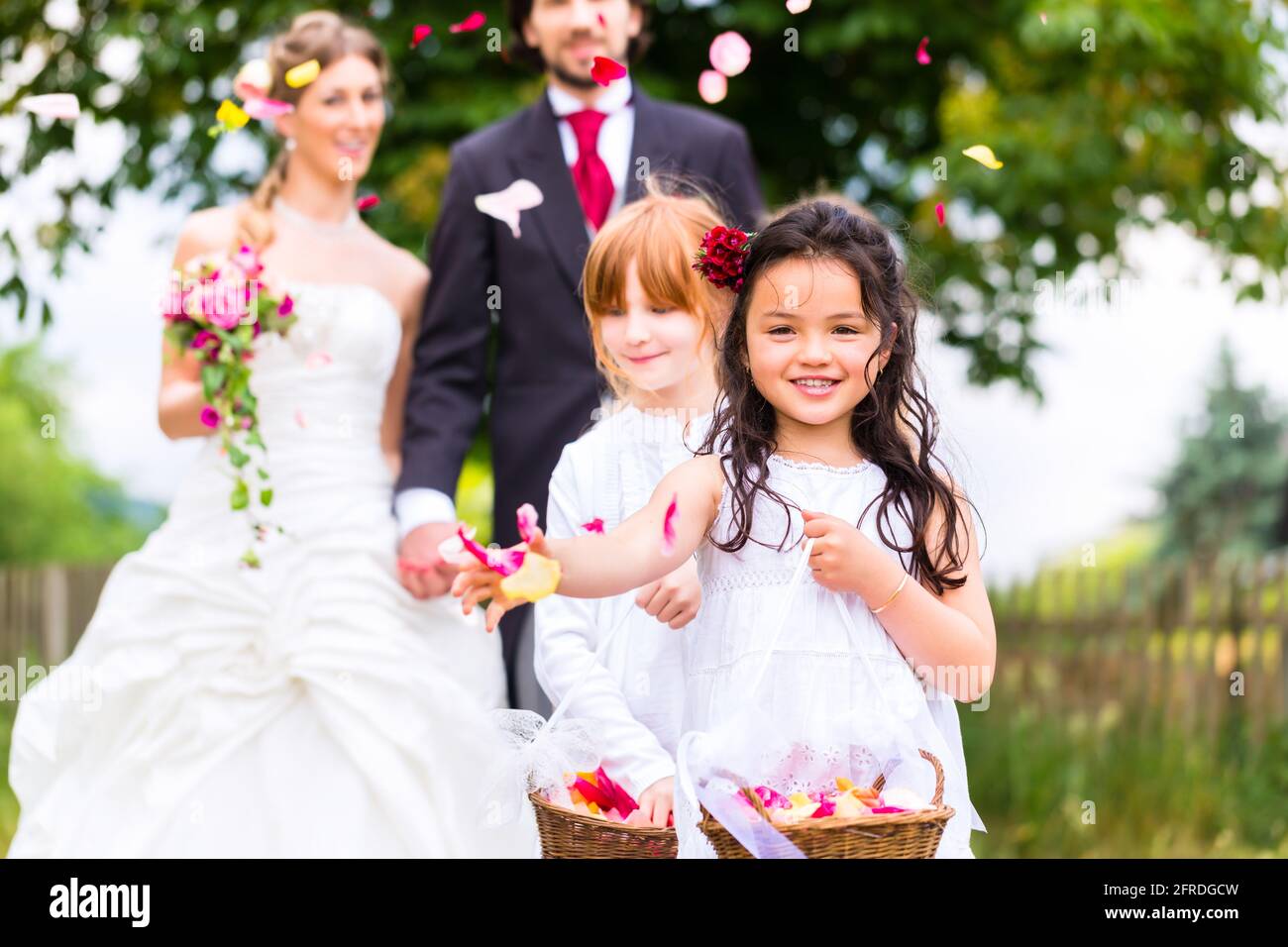 Wedding couple bride and groom with flower children or bridesmaid in ...