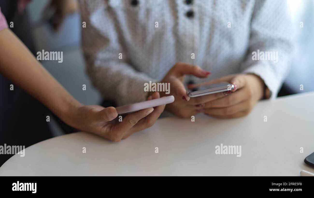 Close up view of two people using two smartphone to consulting on their ...