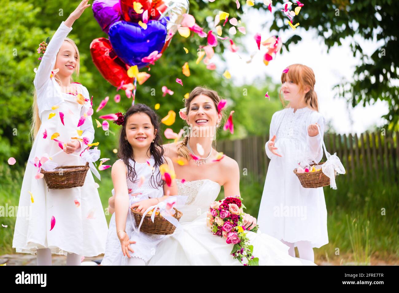 Wedding couple bride and groom with flower children or bridesmaid in ...