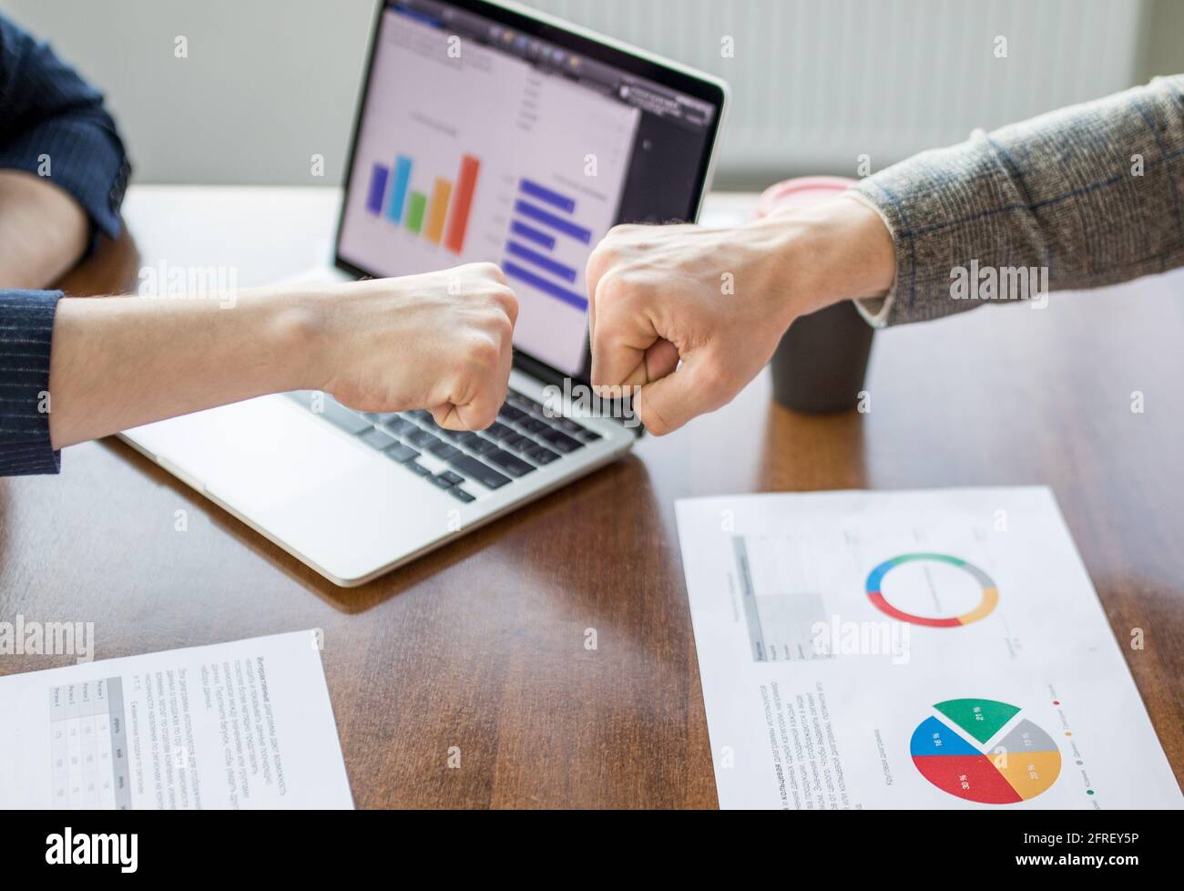 Close up of young businessman and businesswoman making the fist bump on ...