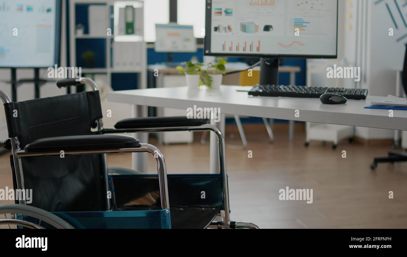 Wheelchair parked in empty office room near desk in start up financial ...