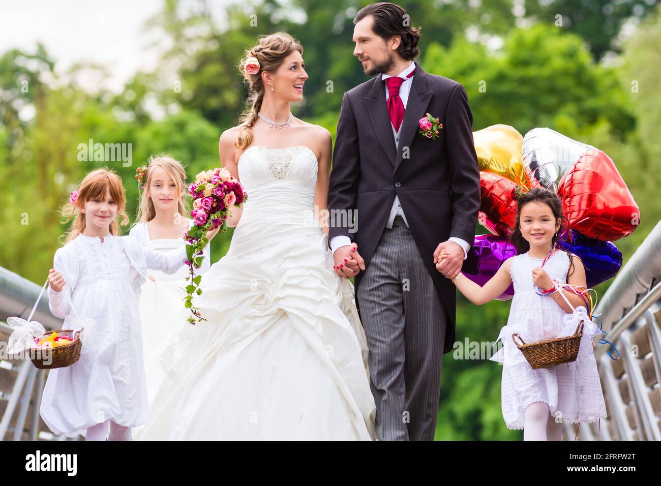 Wedding couple bride and groom with flower children or bridesmaid in ...
