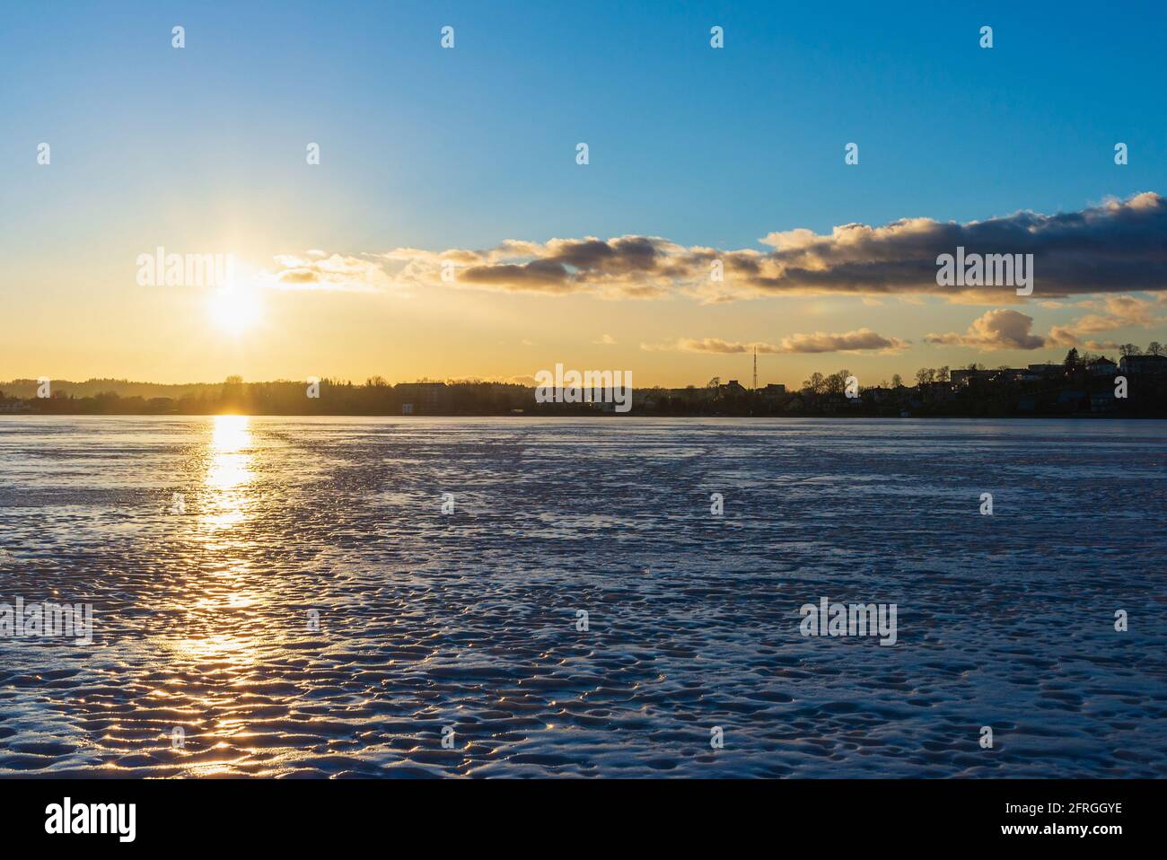 Winter landscape with frozen lake at sunrise or sunset. Lake glistening ...