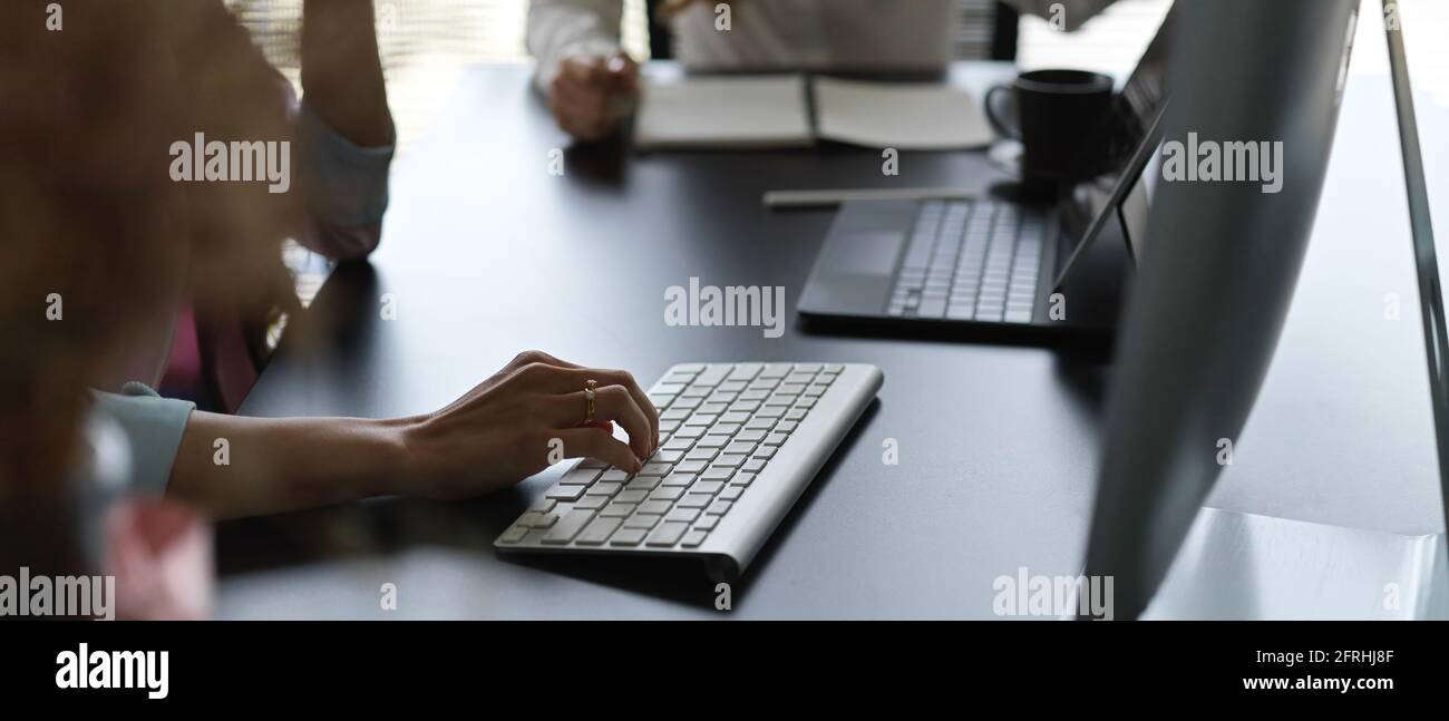 Side view of female hand typing on computer keyboard on worktable in ...