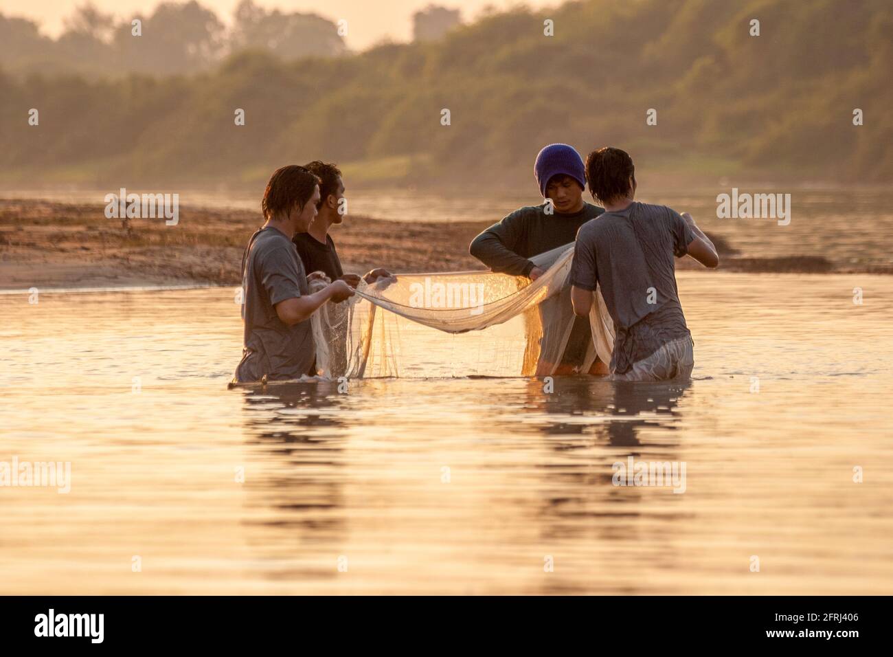 Group of men net fishing in a river in Thailand at sunset Stock Photo ...