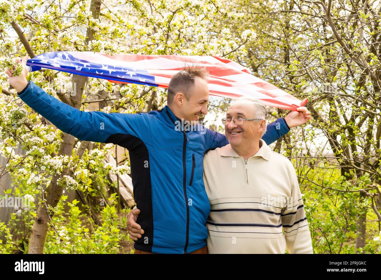 Handsome dad with his little cute sun are laying on green grassy lawn ...