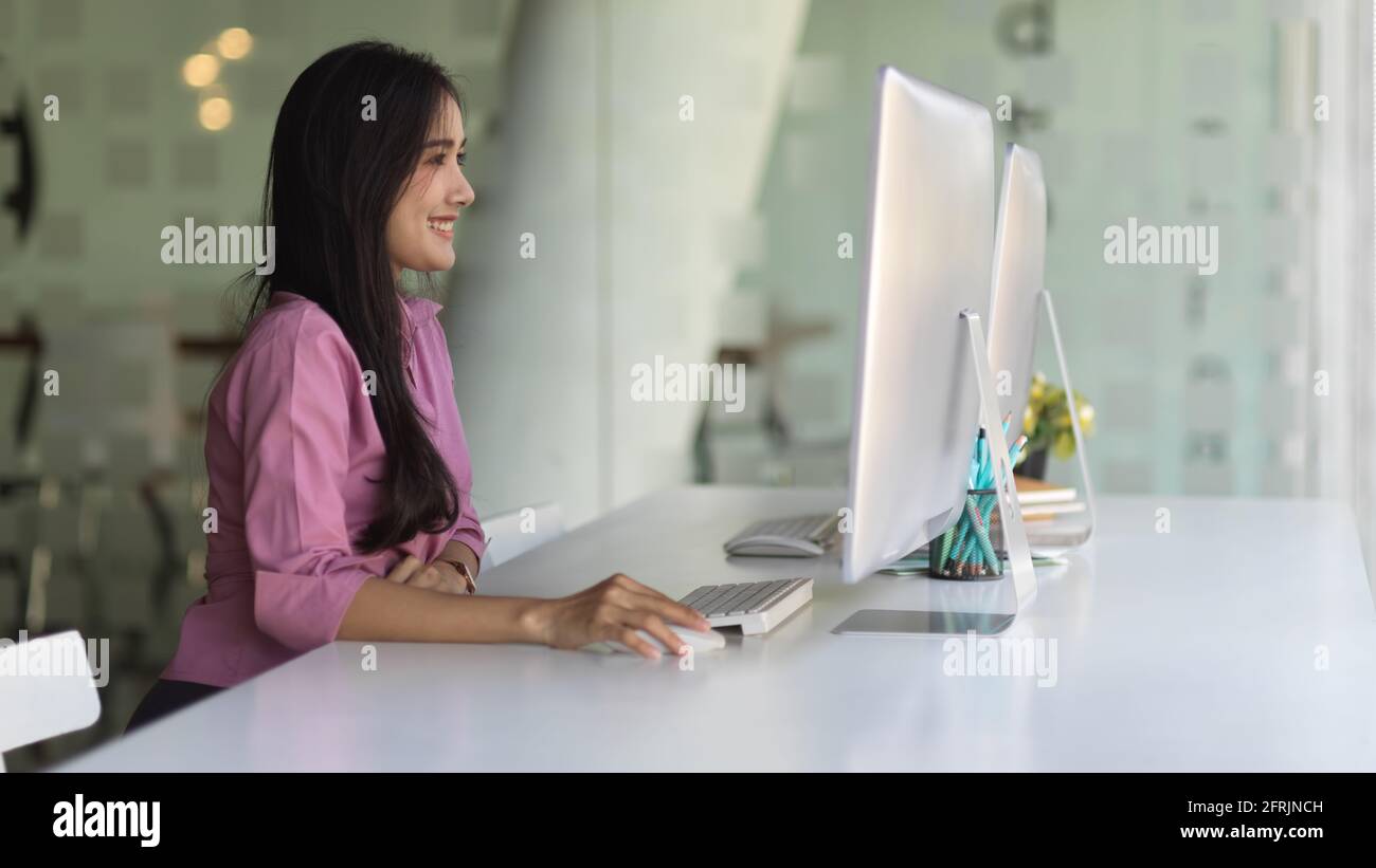 Side view of female office worker working with computer and office ...