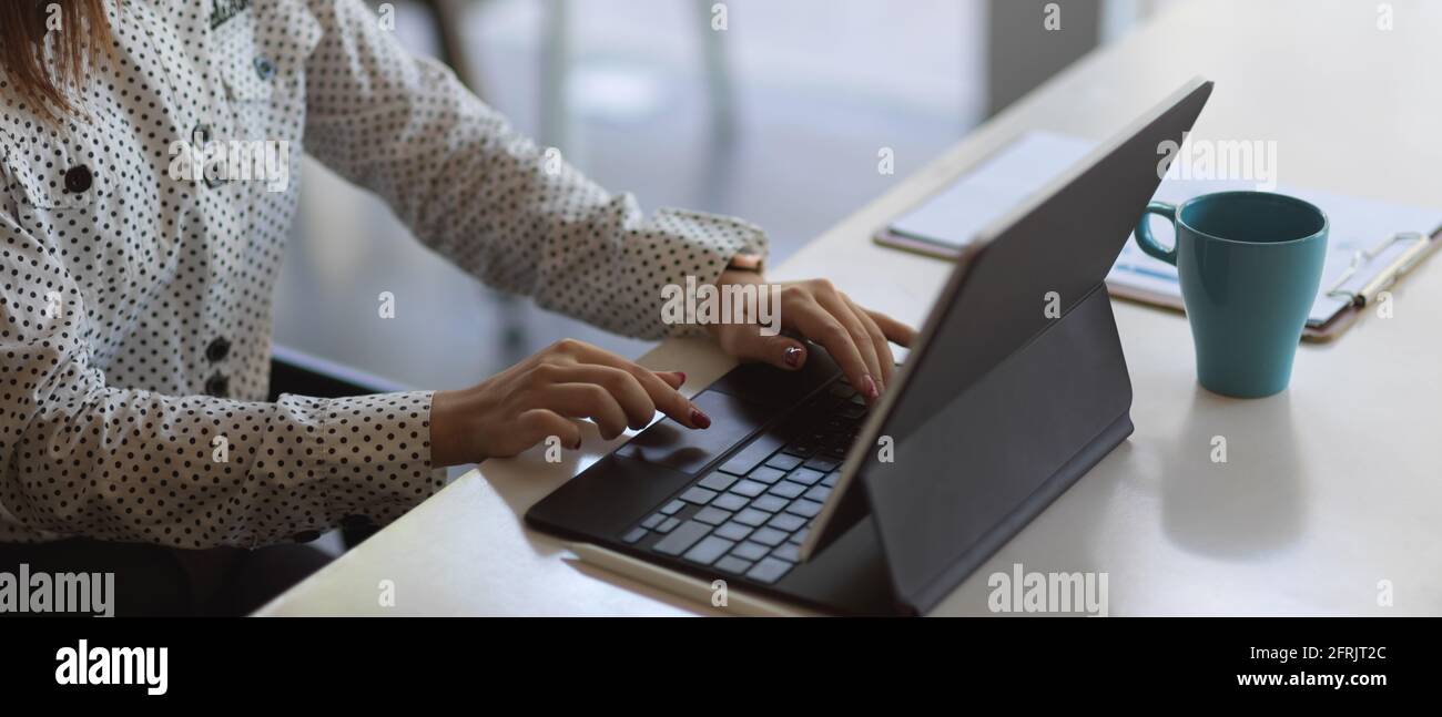 Cropped shot of female hand typing on tablet keyboard on white ...