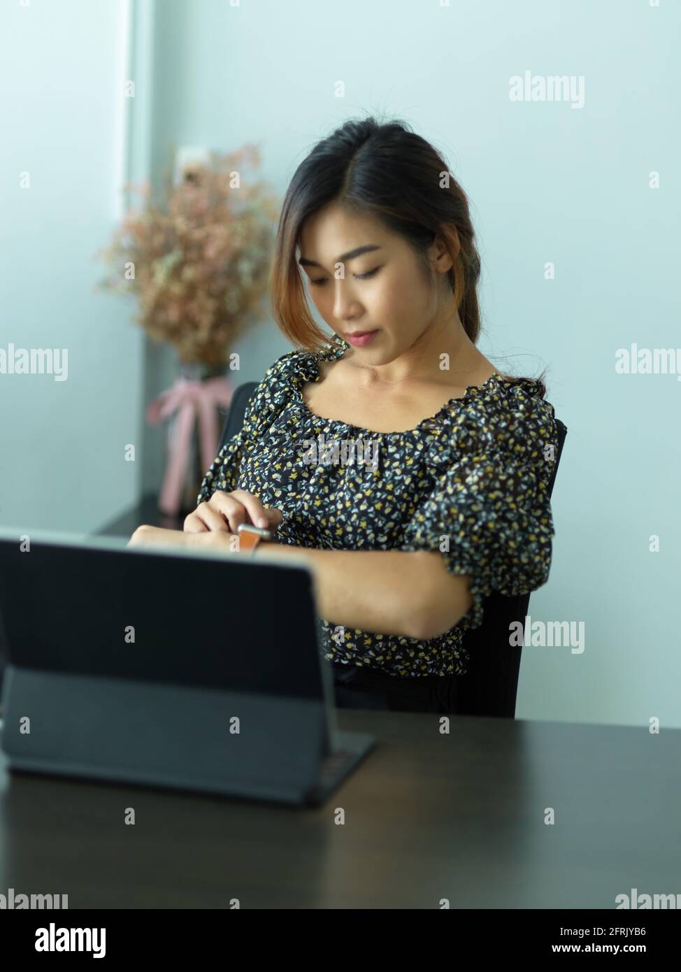 Portrait of female checking message on smartwatch while working in ...