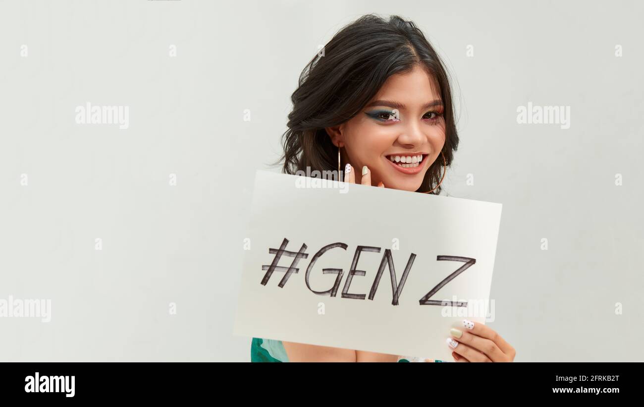 Pretty young excited woman holding #GENZ text in board Stock Photo - Alamy