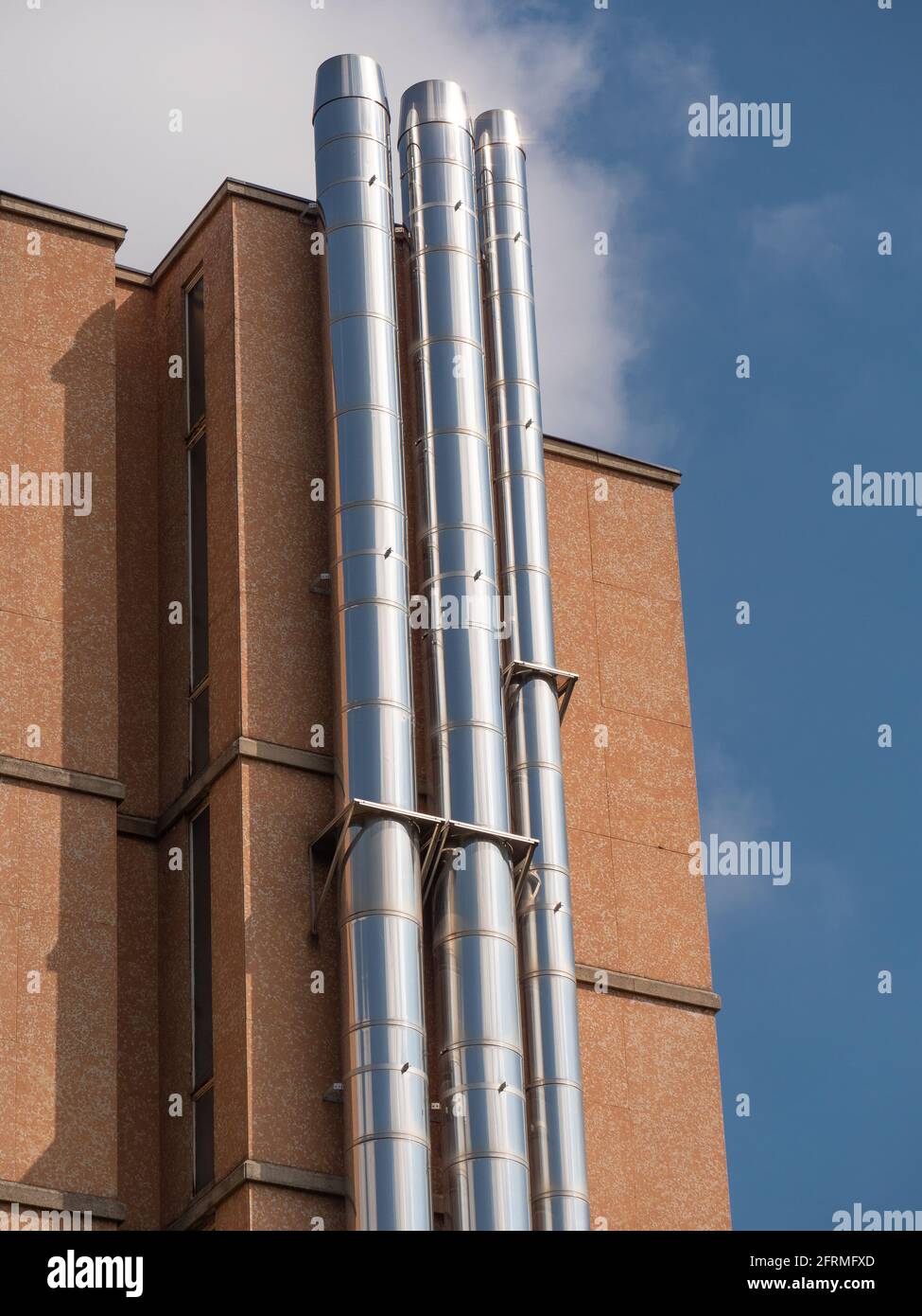 Three Big Vertical Steel Pipes attached to the Exterior Wall of a ...