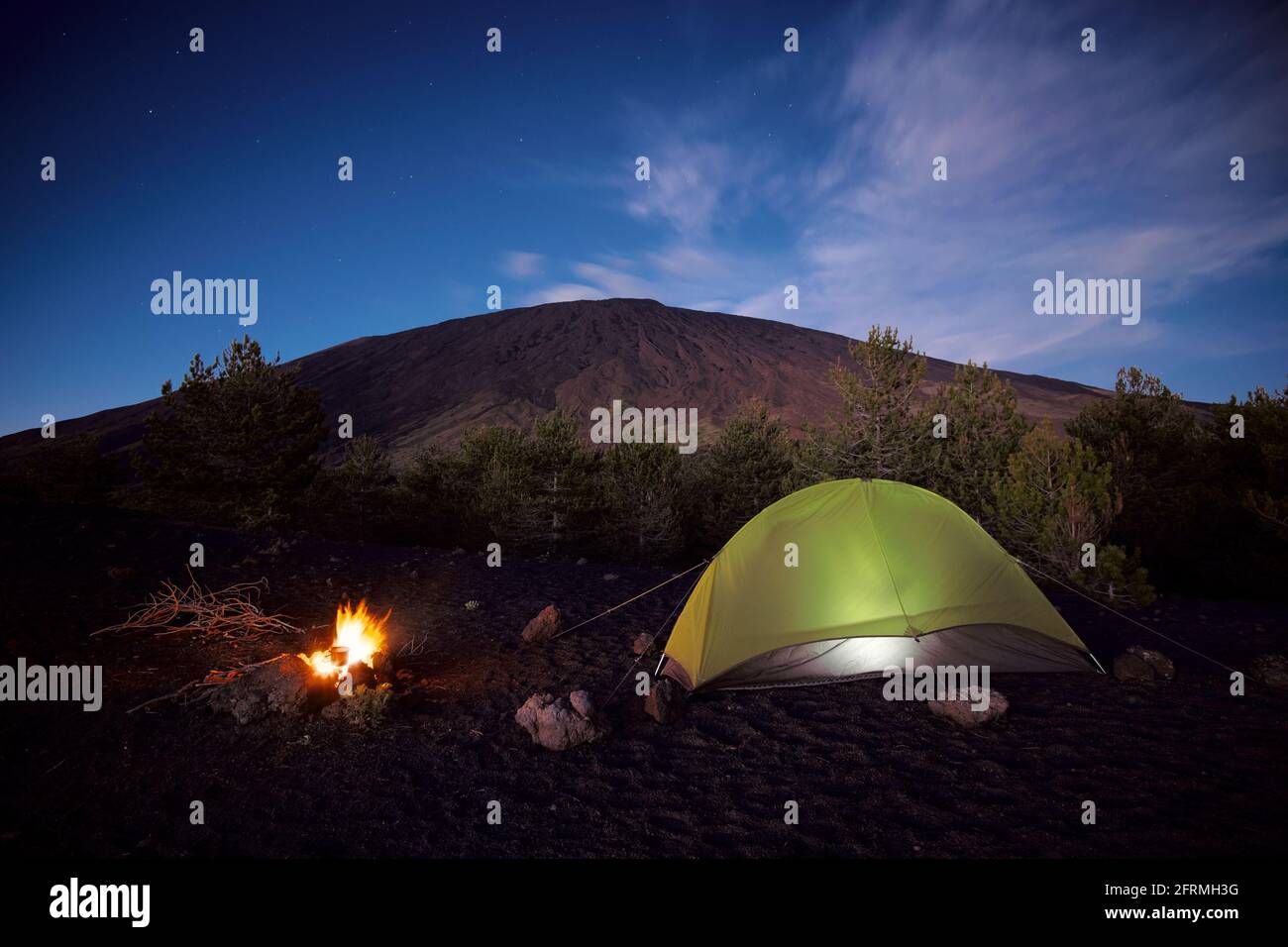 landscape in Sicily night with campfire and illuminated tent below Etna ...