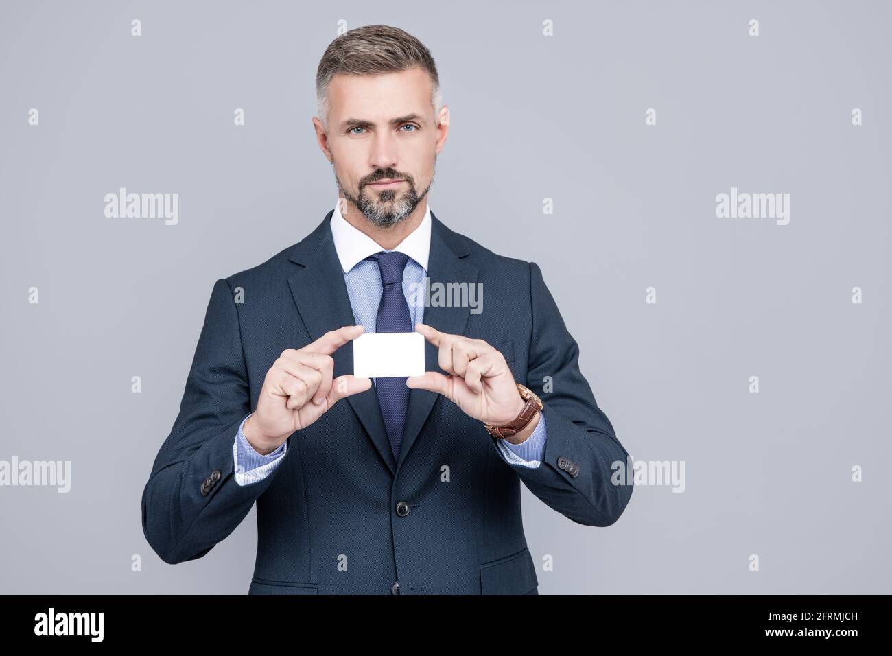 mature man banker with grizzled hair in suit showing credit or debit ...
