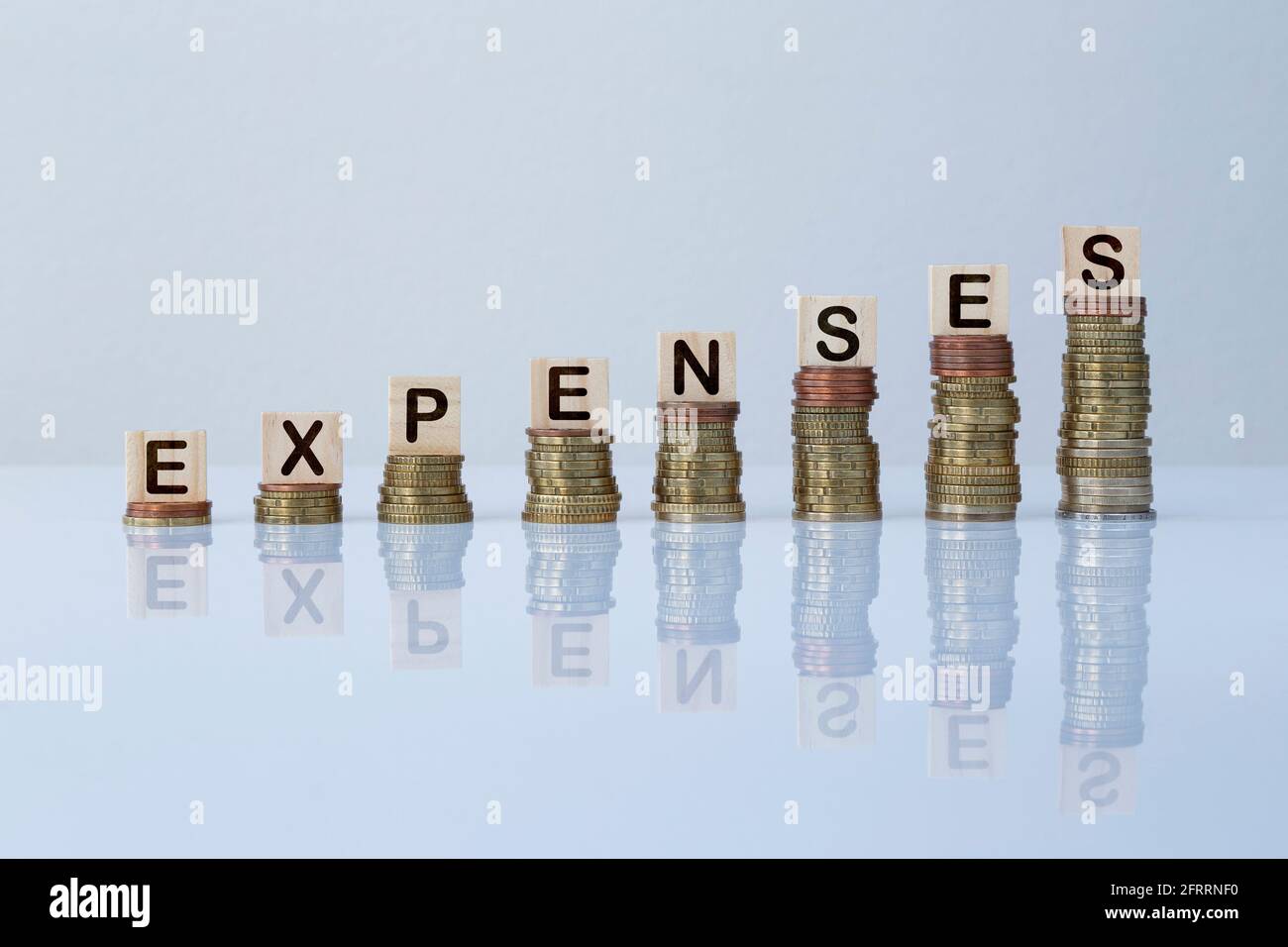 Word "EXPENSES" on wooden blocks on top of ascending stacks of coins on ...
