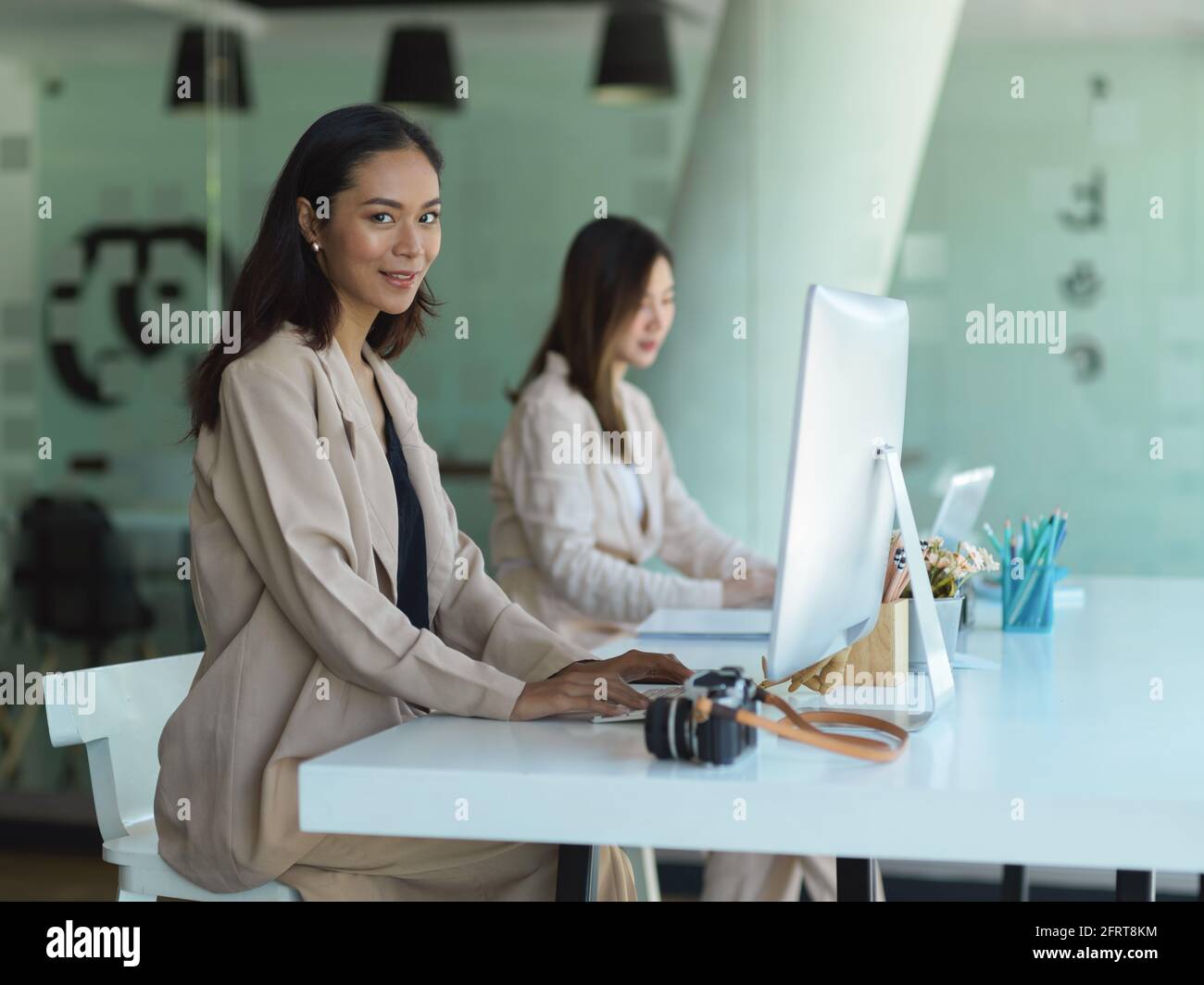 Side view of female office worker smiling to camera while working with ...