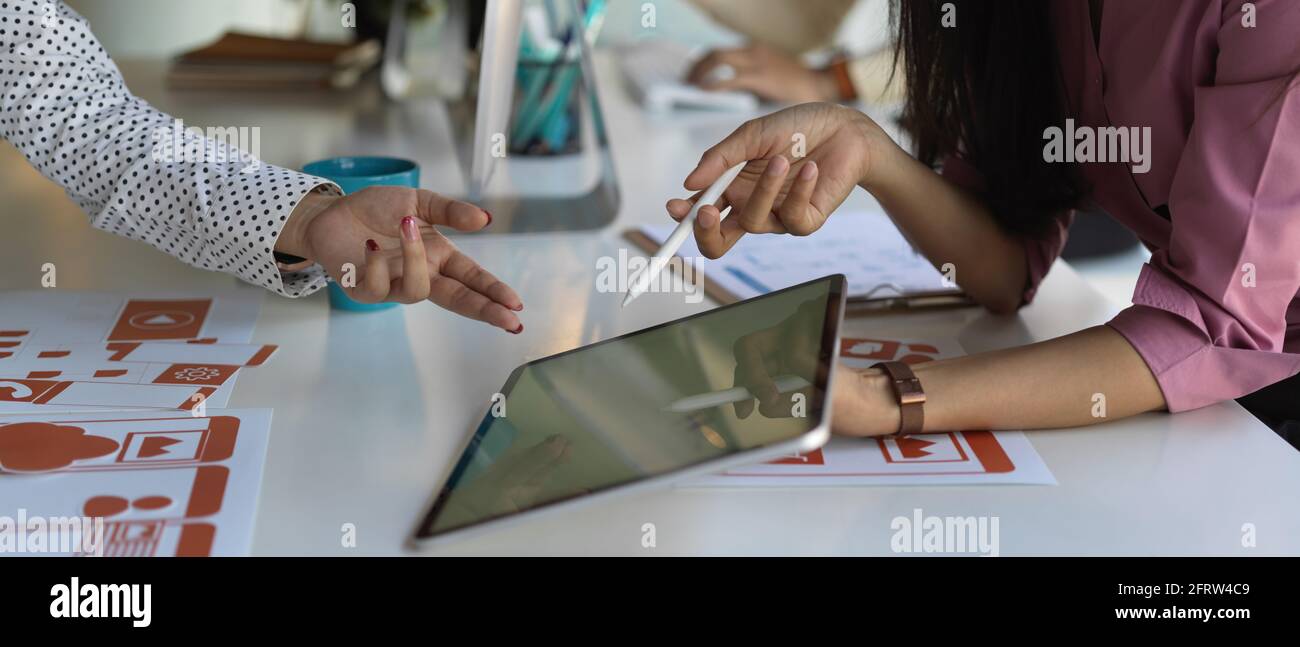 Side view of UI developer team meeting on their project with tablet and ...