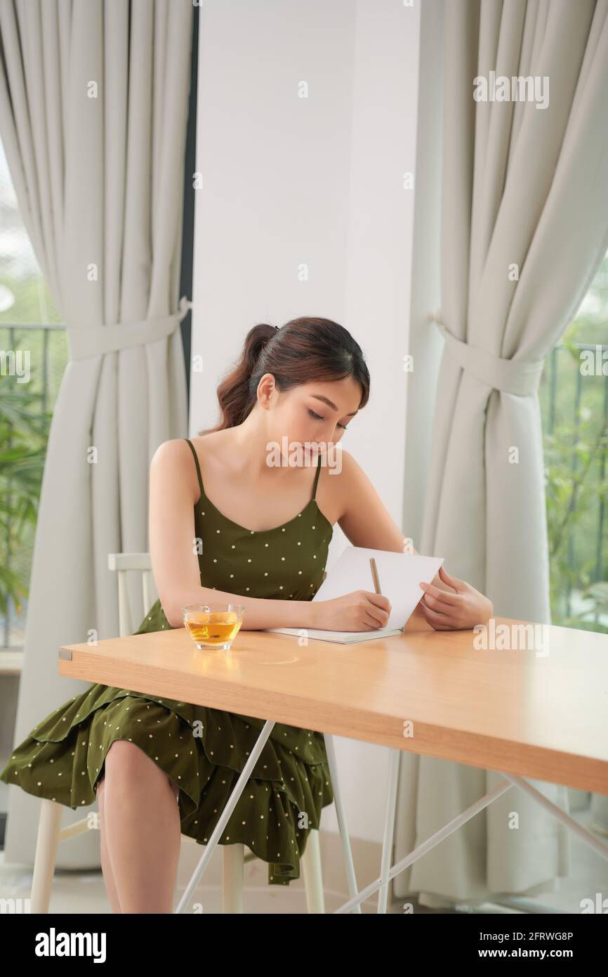Pretty asian woman writing at home in the living room Stock Photo - Alamy