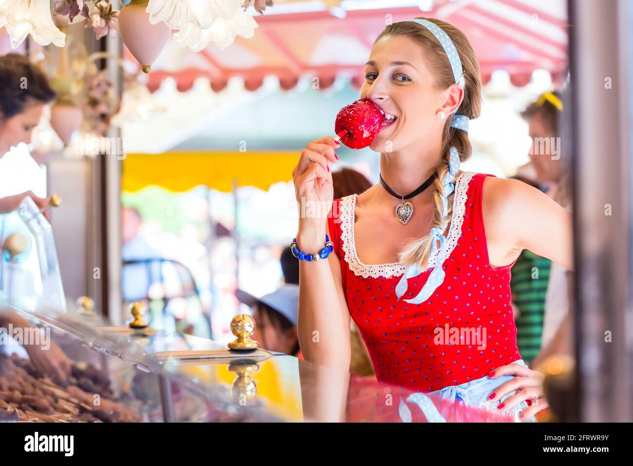 Woman eating candy apple at Oktoberfest wearing Dirndl Stock Photo - Alamy