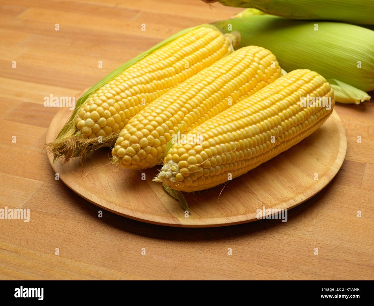 Close up view of corns and corn on the cop on wooden tray on wooden ...