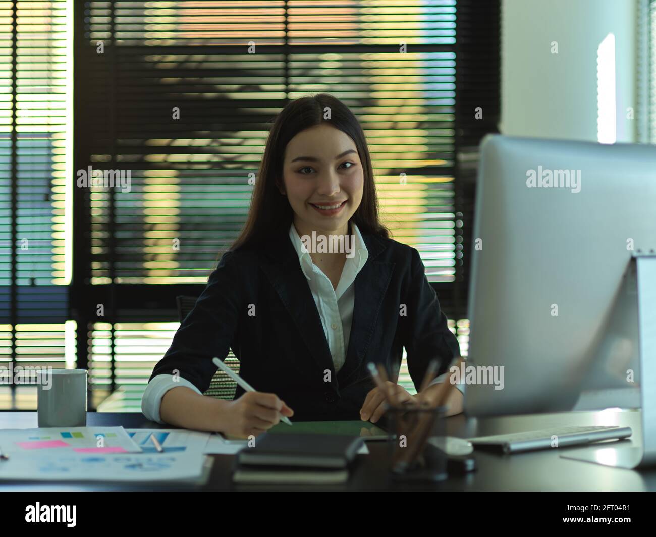 Portrait of businesswoman smiling to camera while working with computer ...