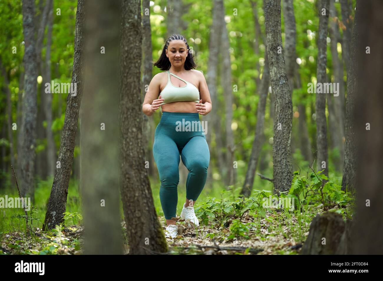 Beautiful plus size runner woman running on a dirt road in the forest ...
