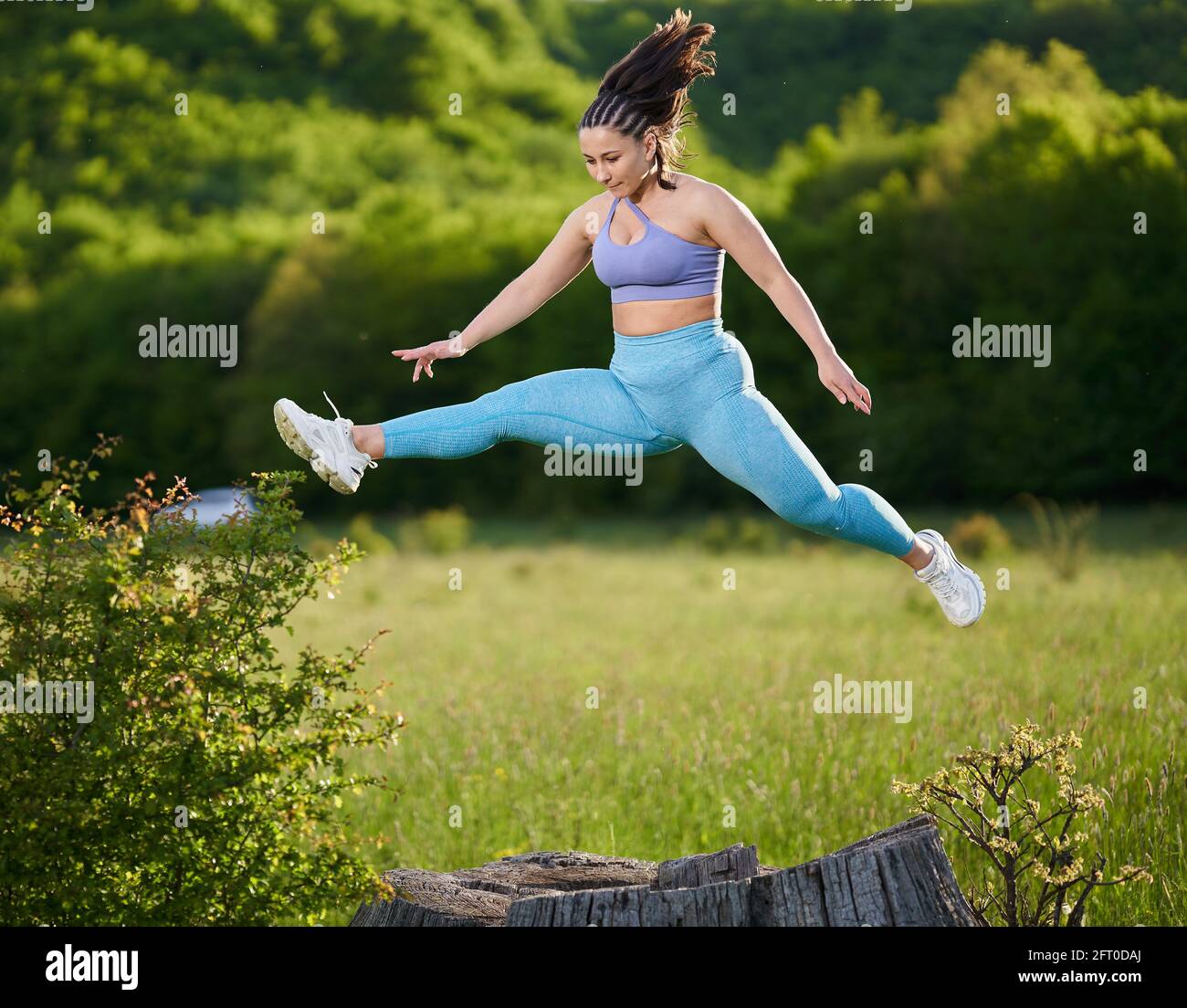 Size plus young woman in sport attire doing fitness exercises with body ...