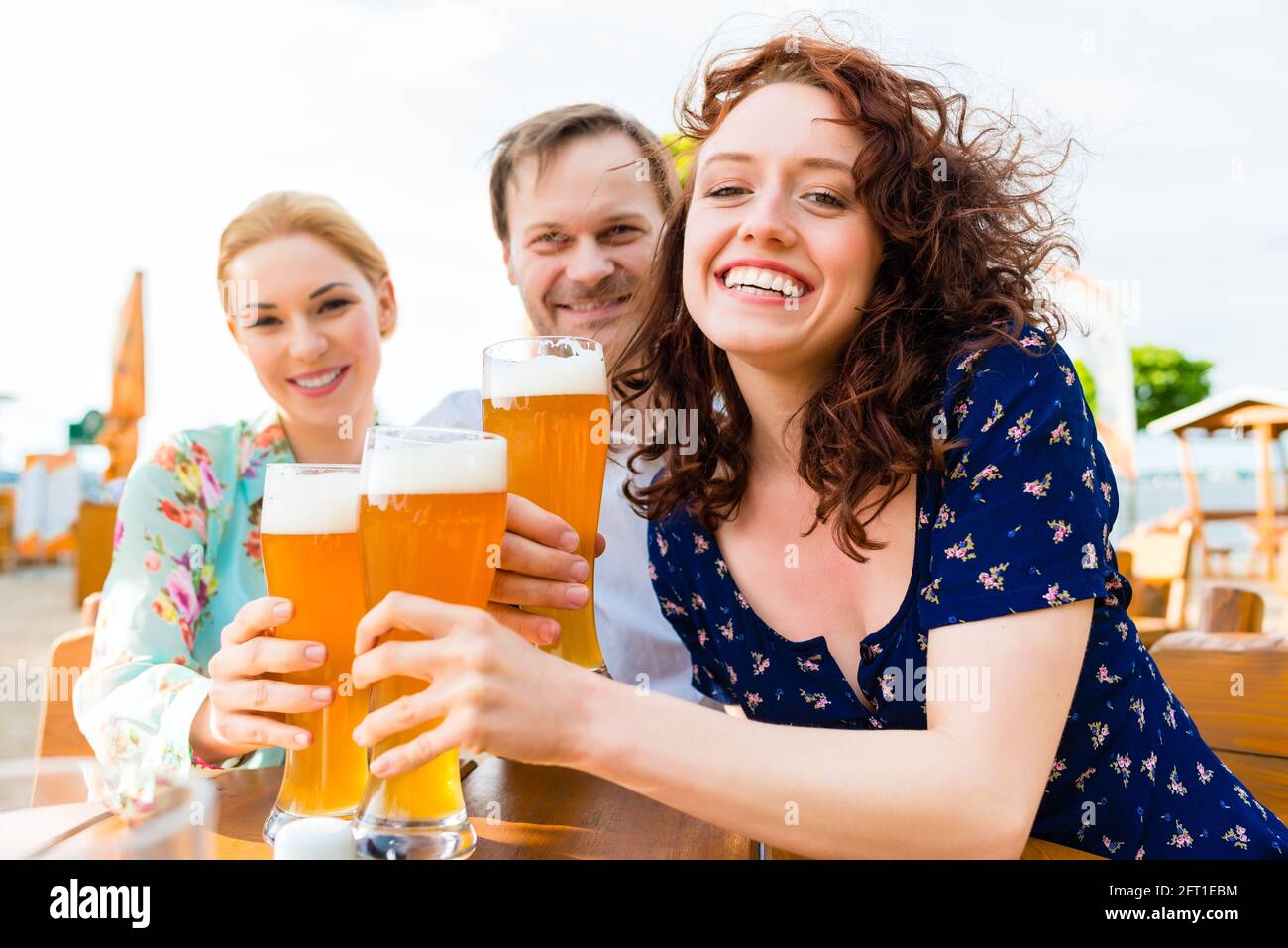 Friends toasting with beer in garden restaurant Stock Photo - Alamy