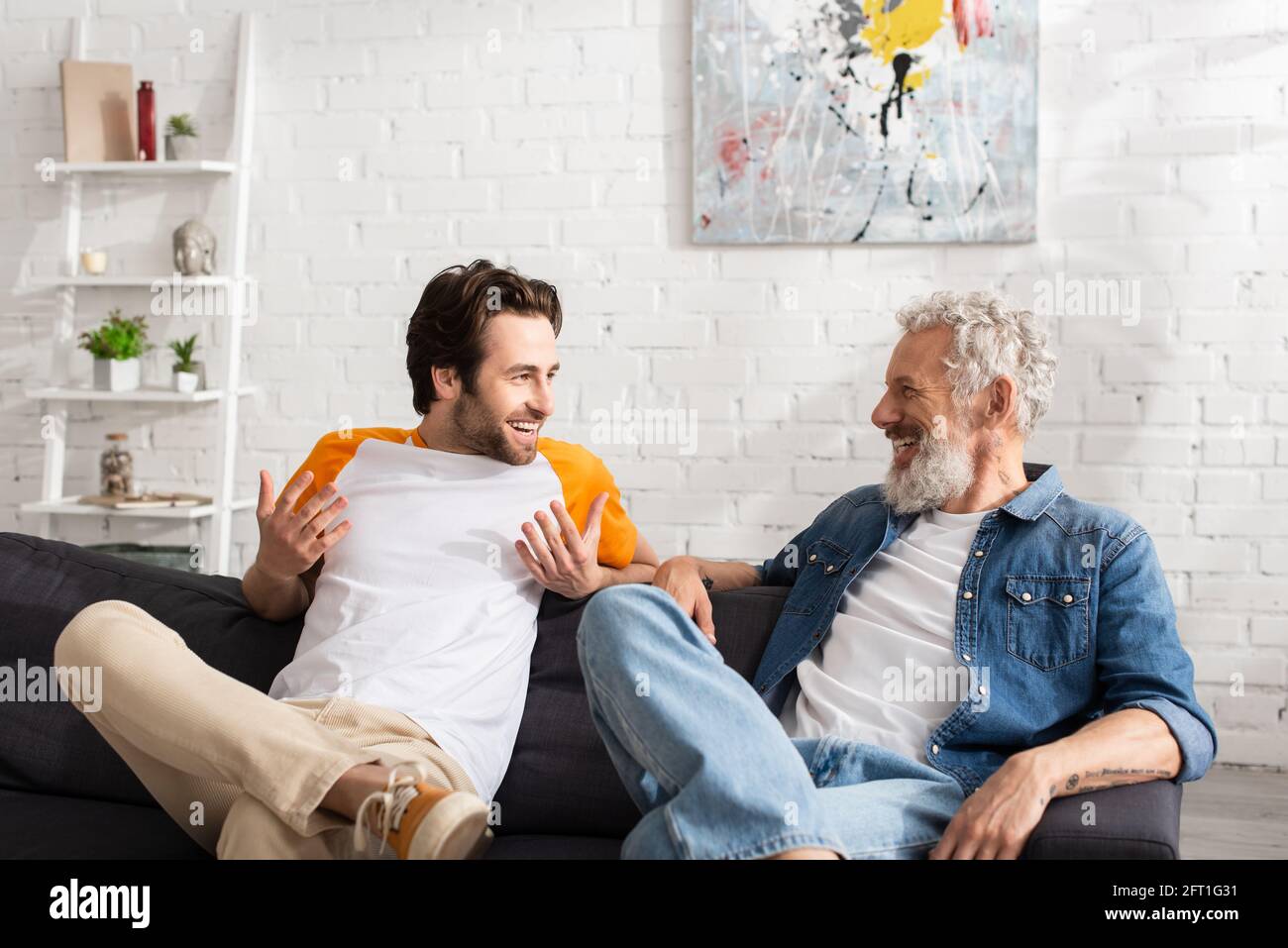 Young son smiling while talking to father at home Stock Photo - Alamy