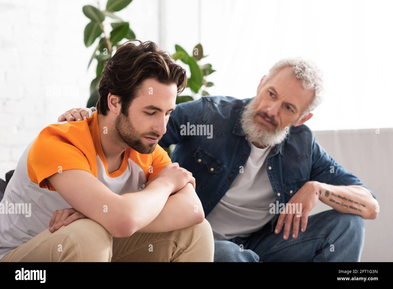 Sad man sitting near blurred father Stock Photo - Alamy