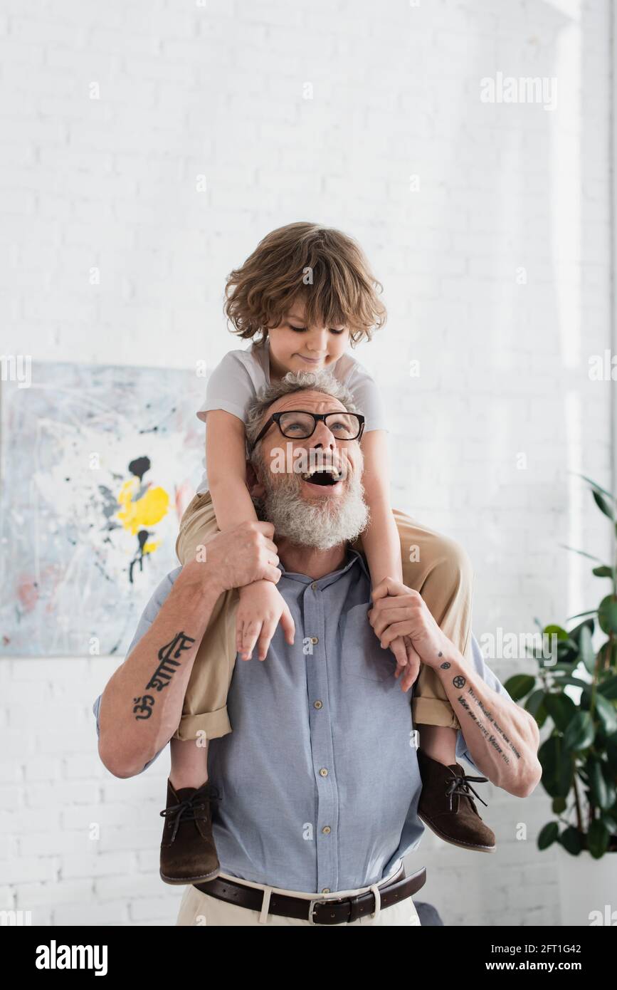 Cheerful granddad holding grandson at home Stock Photo - Alamy