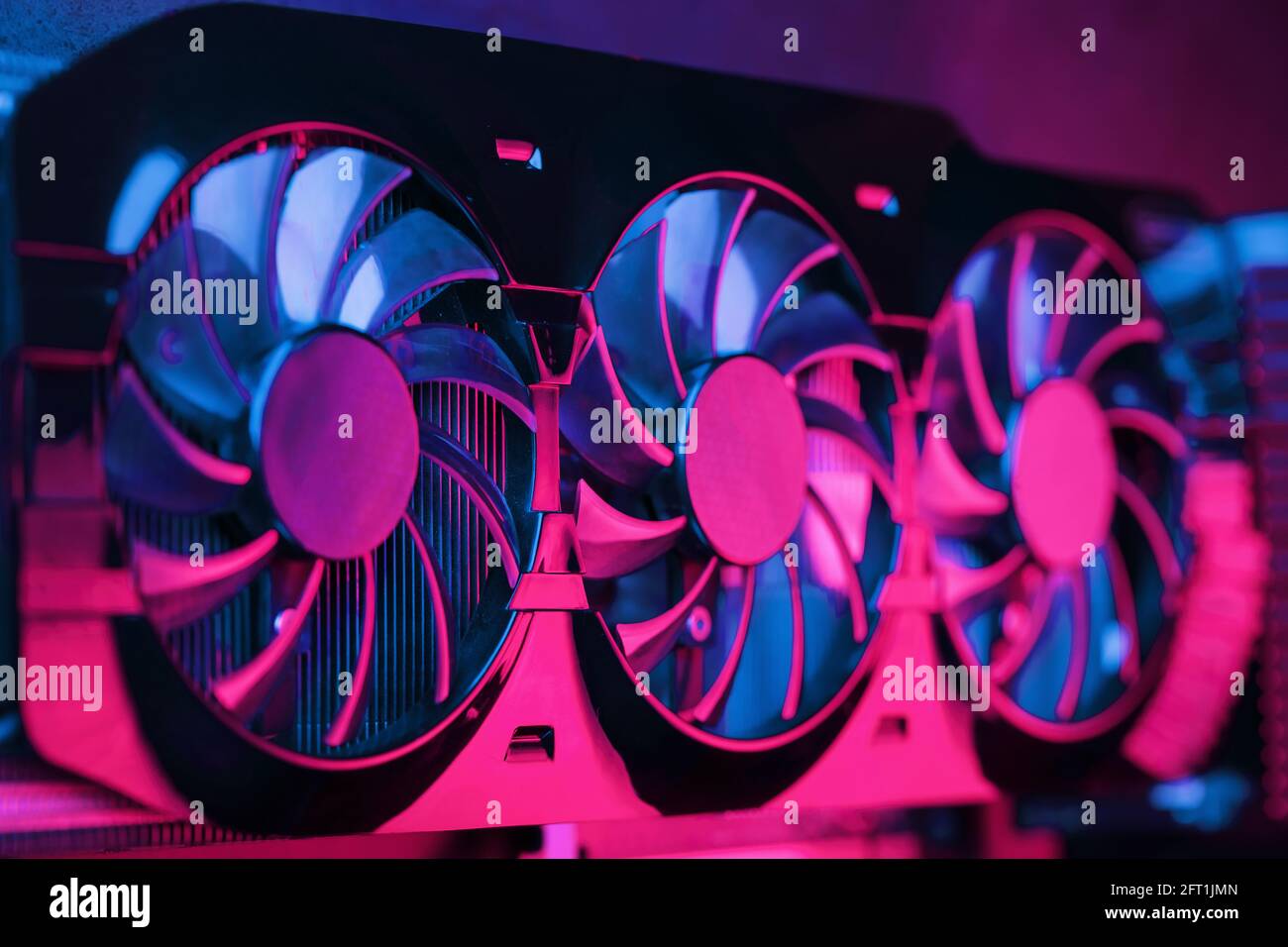 A graphics card with a row of fans with a cyanotic purple backlight in ...