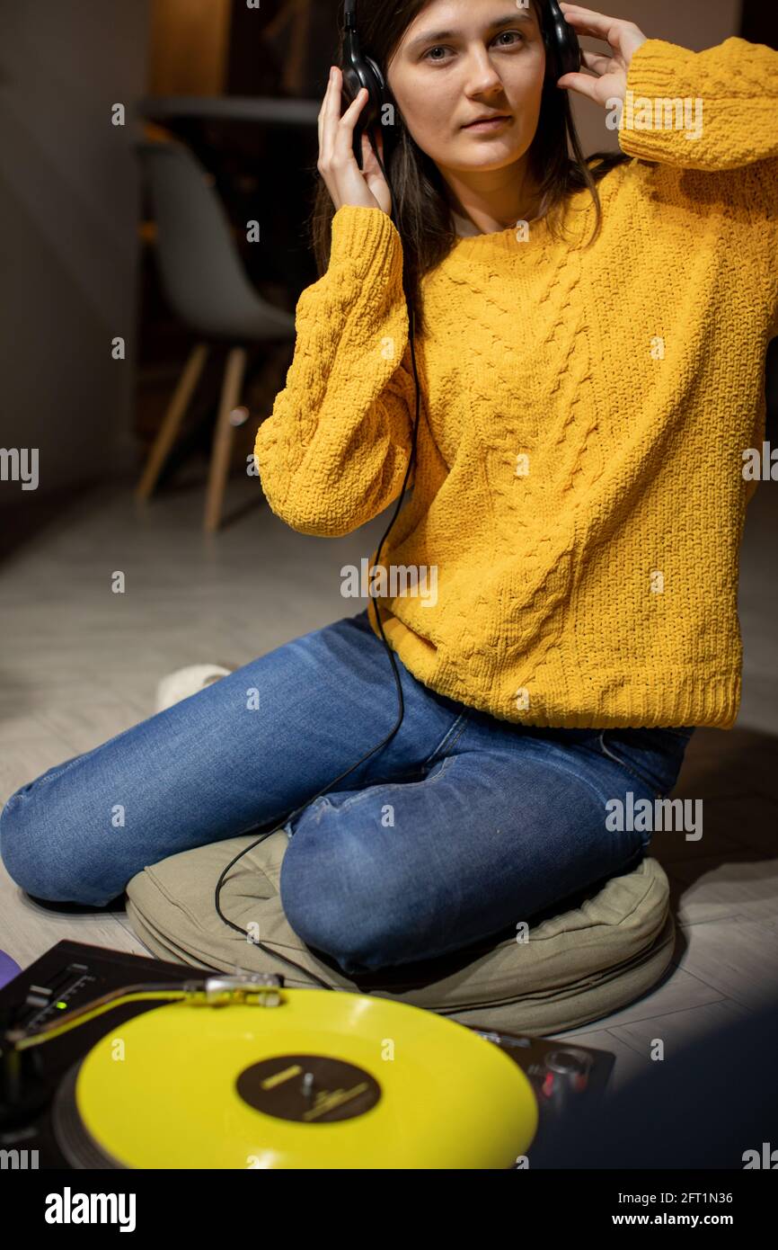 girl sitting on floor enjoys to music with headphones and analog ...