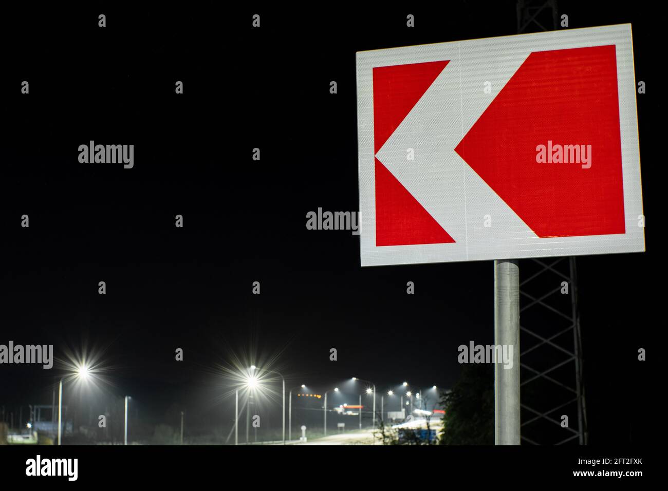 Left turn signs against the night sky and streetlights. Road signs warn ...