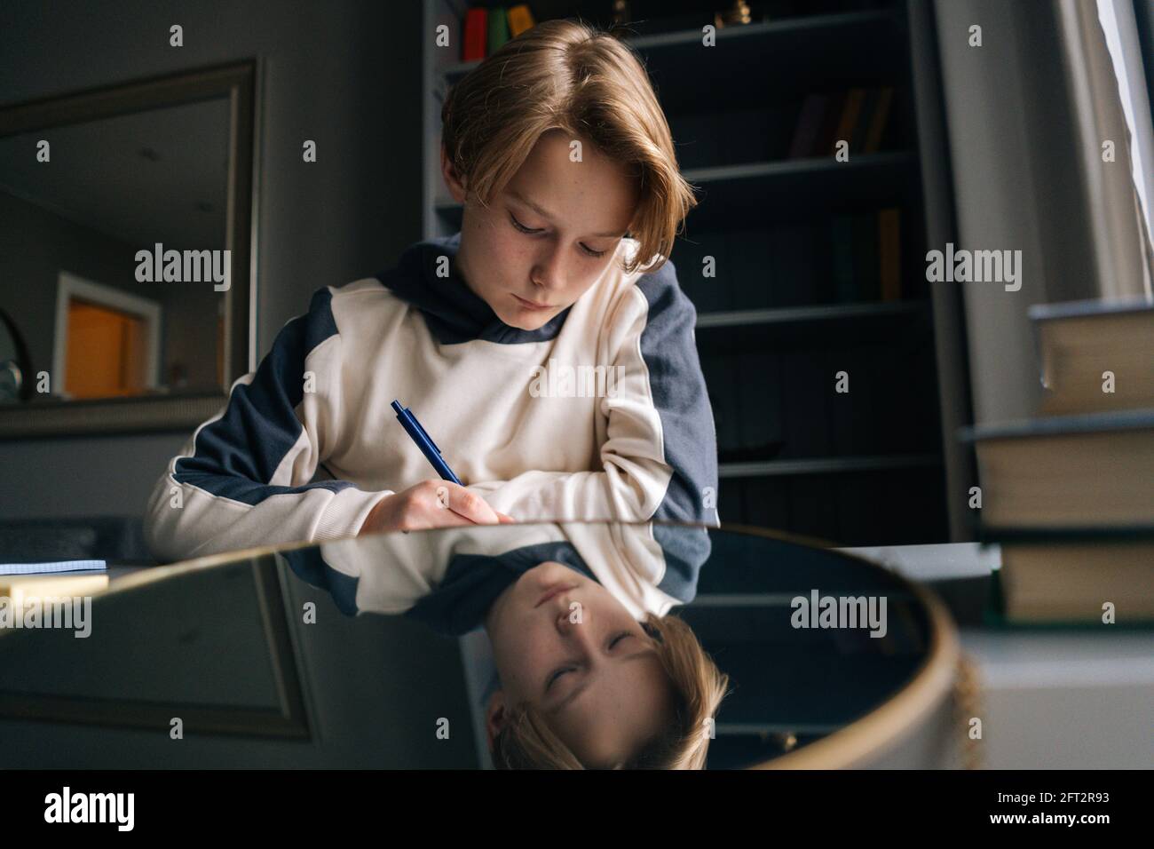 Close-up face of concentrated pupil boy writing notes in paper workbook ...