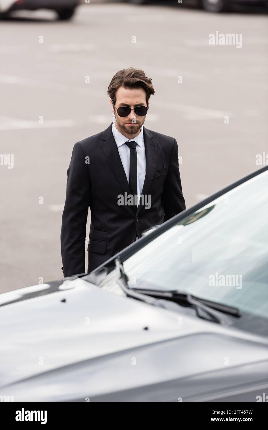 bodyguard in suit and sunglasses with security earpiece standing near ...