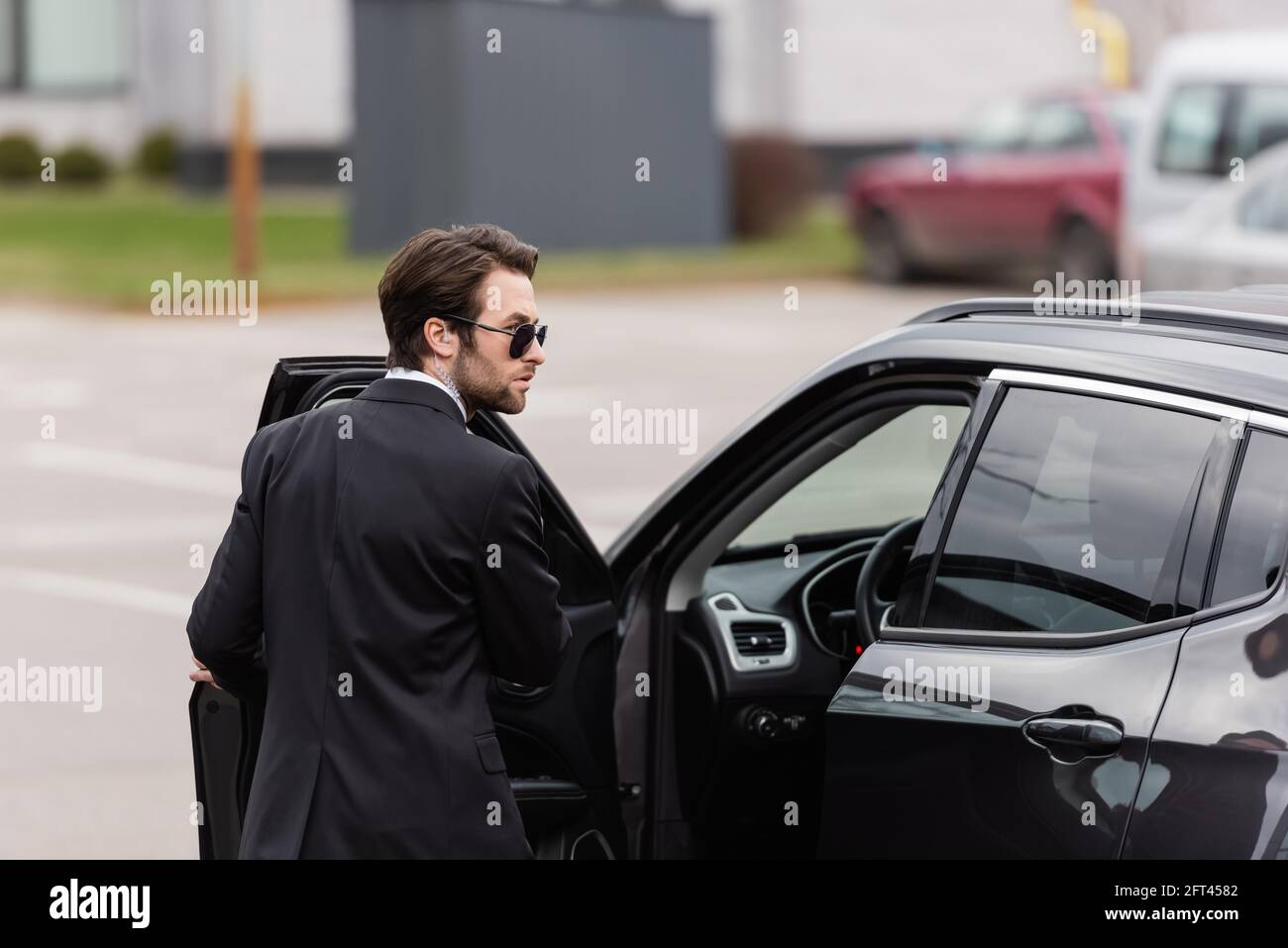 bearded bodyguard in suit and sunglasses with security earpiece near ...